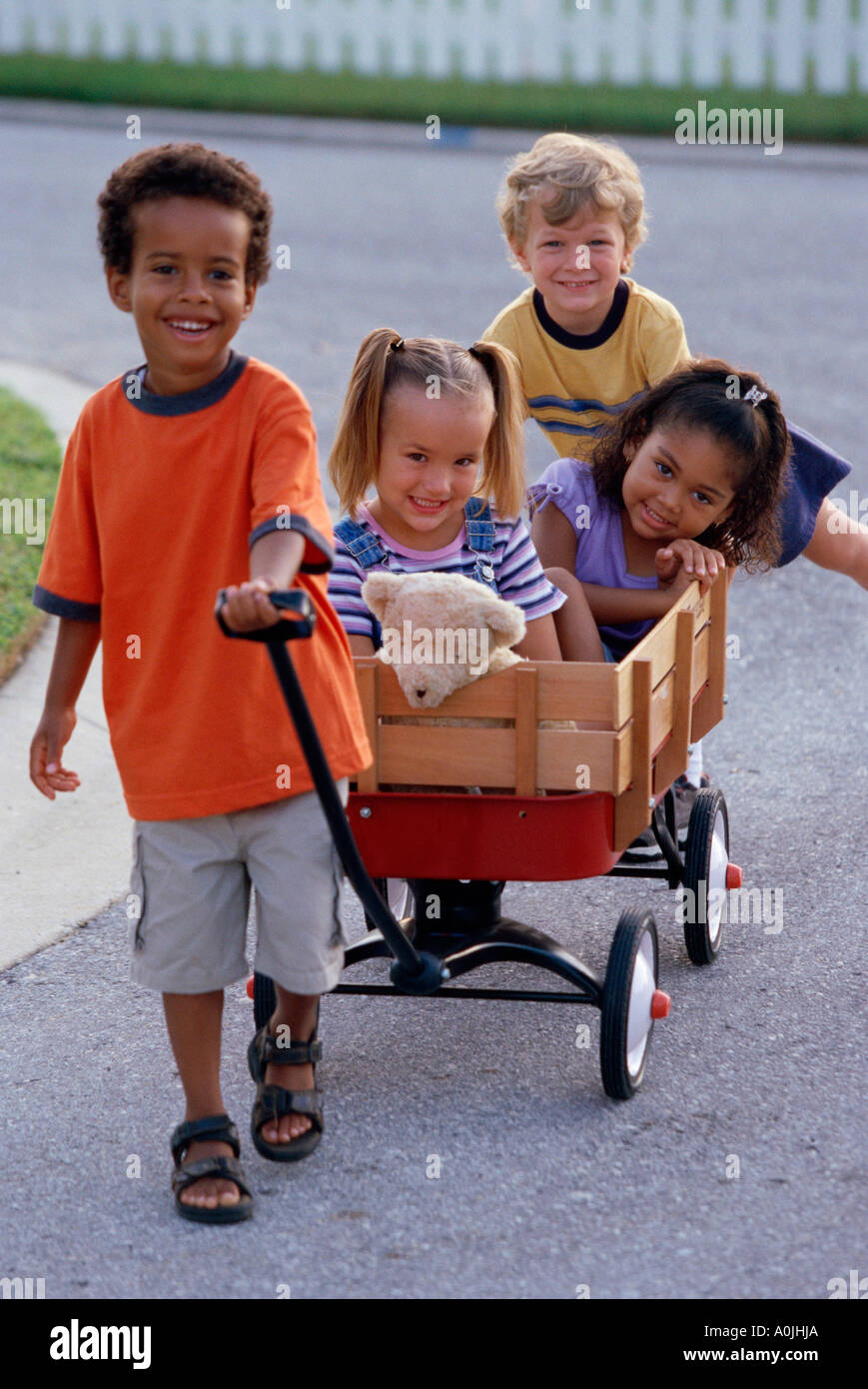Portrait of two boys and two girls playing with a push cart Stock Photo ...