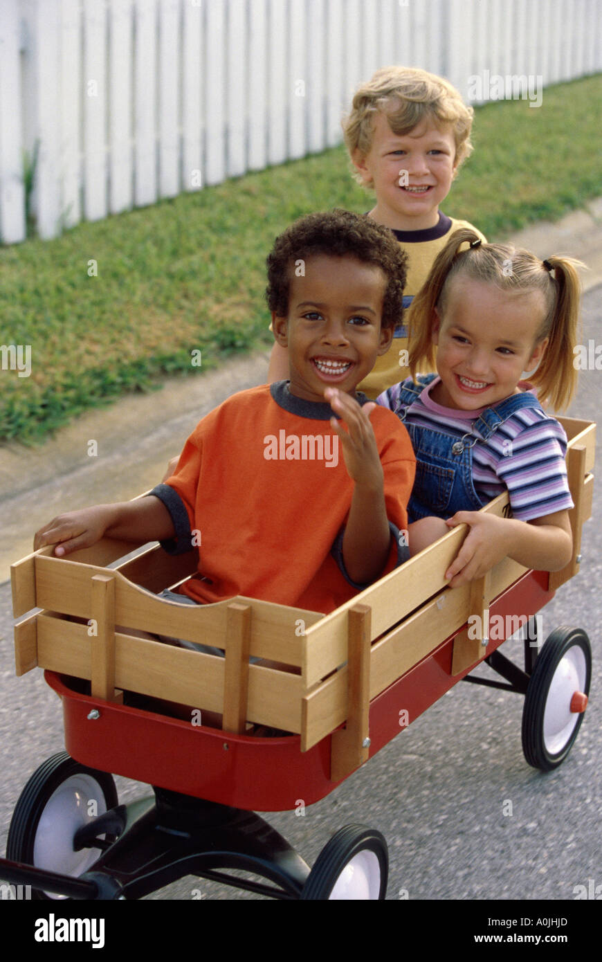 Portrait of two boys and a girl playing with a push cart Stock Photo ...