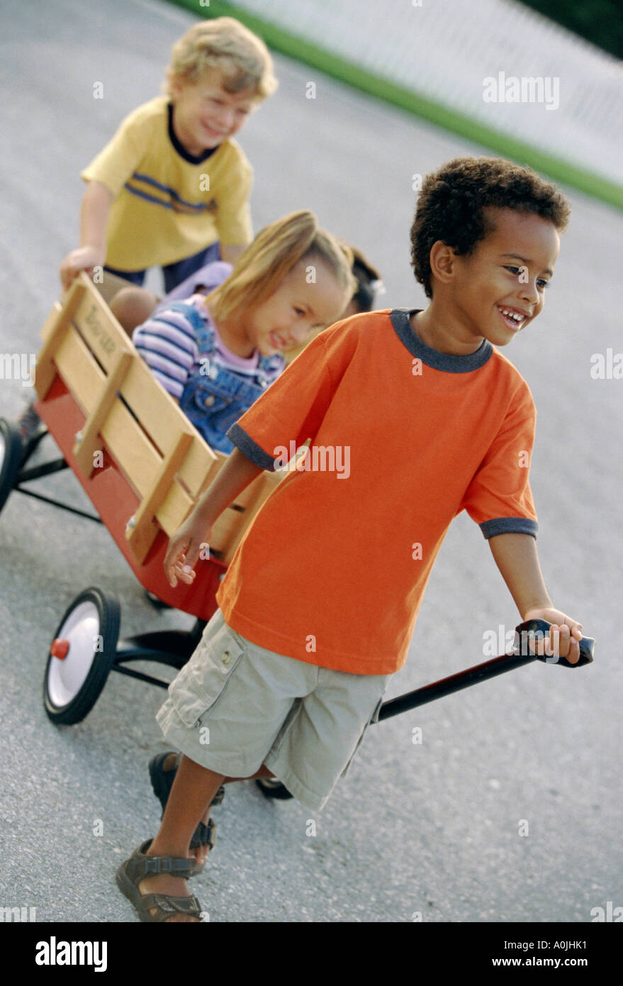 Two boys and a girl playing with a push cart Stock Photo - Alamy