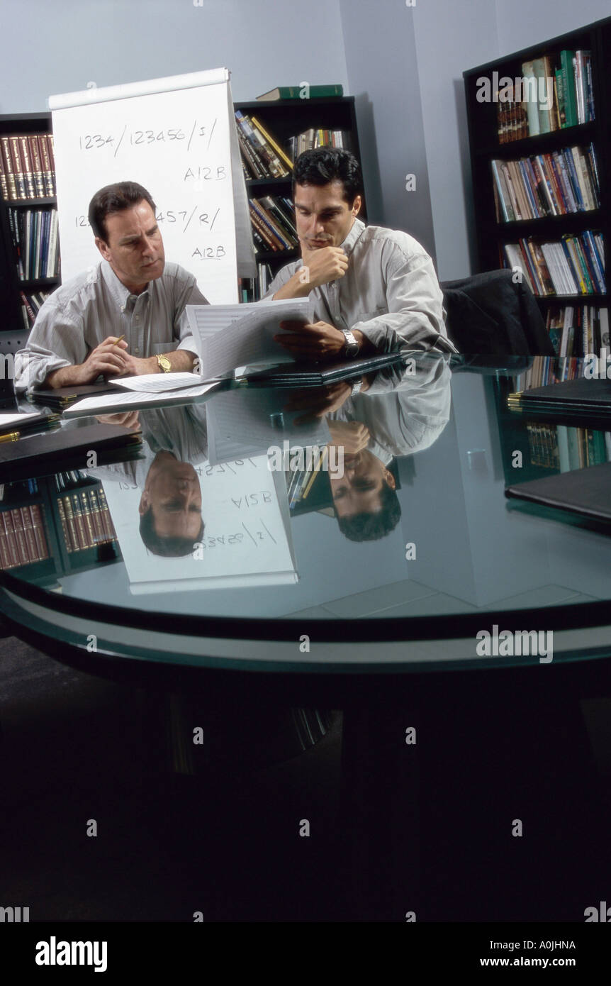 Two businessmen seated at a table reading documents Stock Photo - Alamy