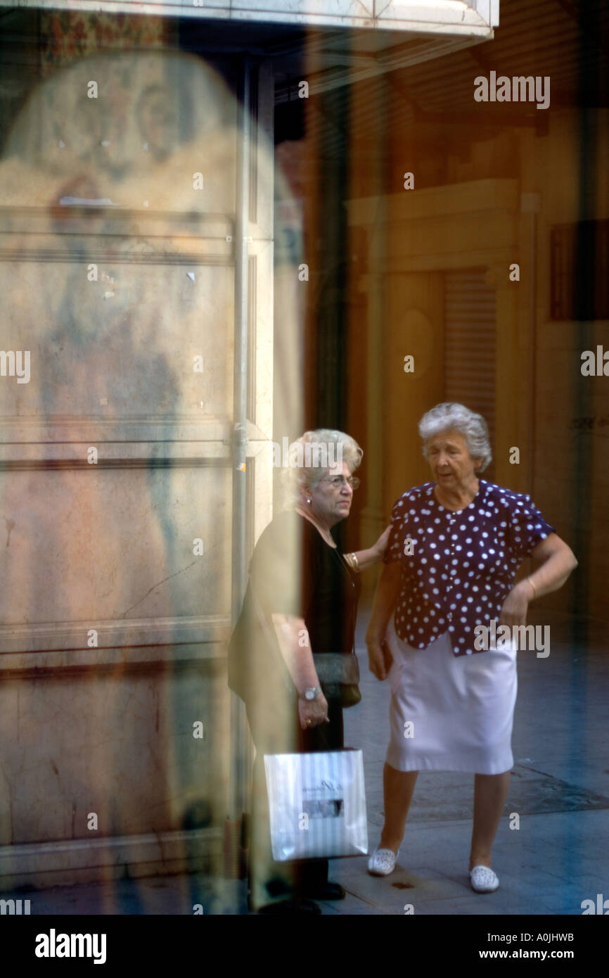 Two elderly Spanish woman gossiping on street cornet in Alicante old ...