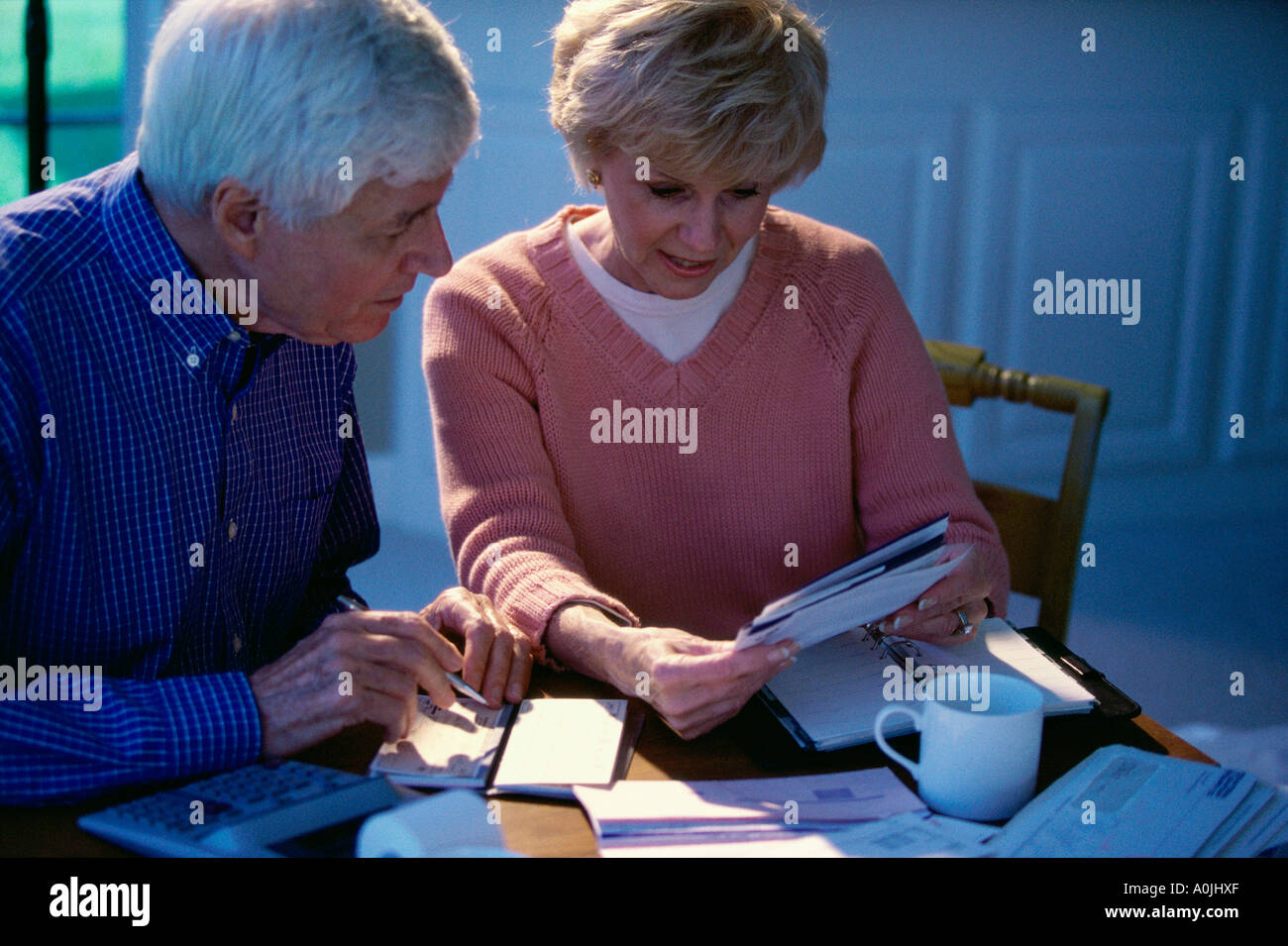 Senior couple writing a check Stock Photo - Alamy