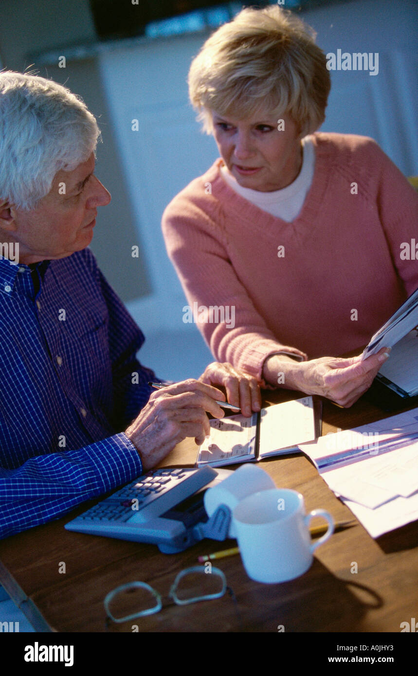 Senior couple writing a check Stock Photo - Alamy