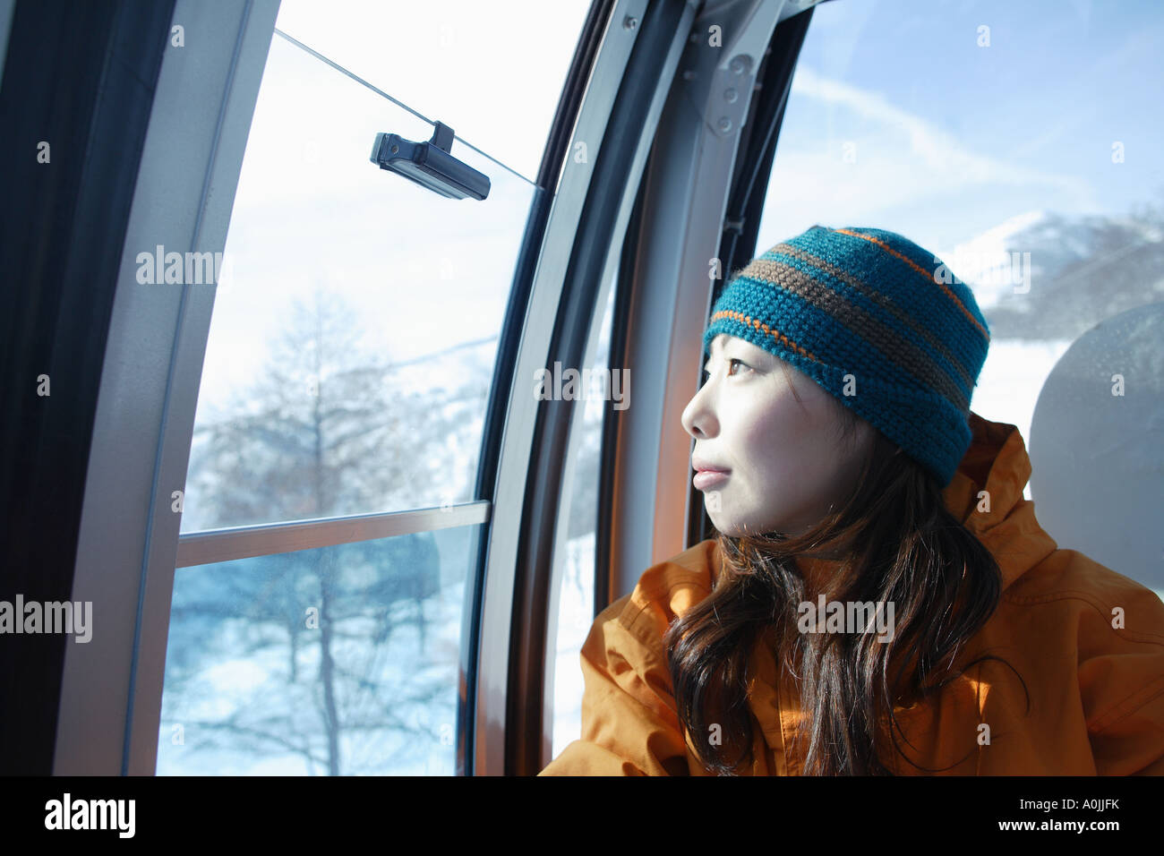 Asian female snowboarder in ski lift Stock Photo - Alamy