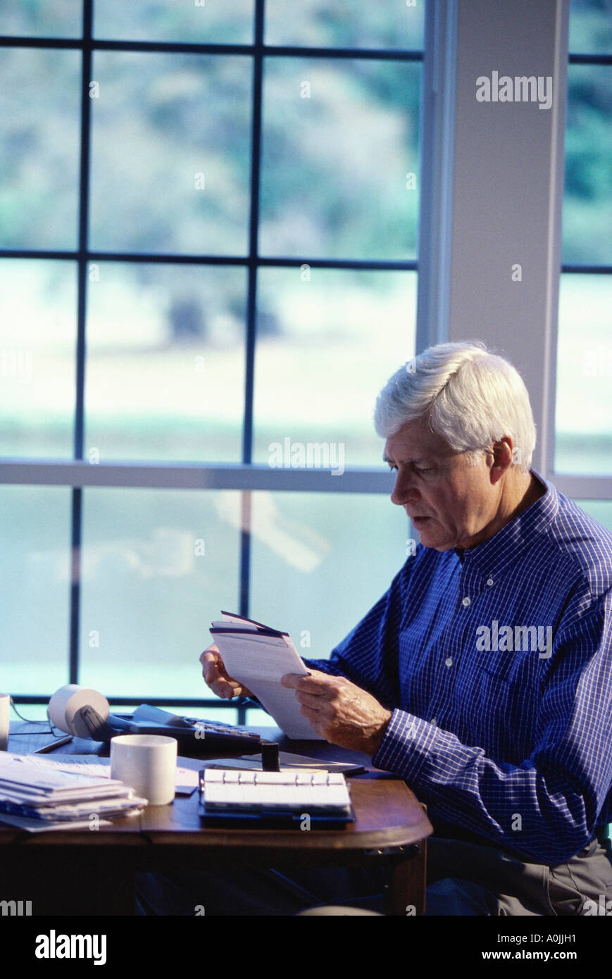 Senior man sitting calculating bills Stock Photo - Alamy