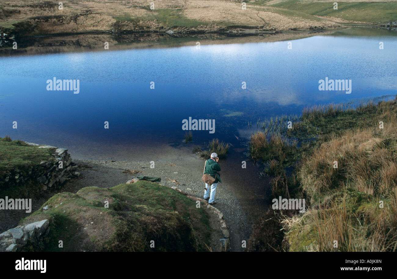 Man taking photograph at Pinkery Pond in Exmoor forest Stock Photo - Alamy
