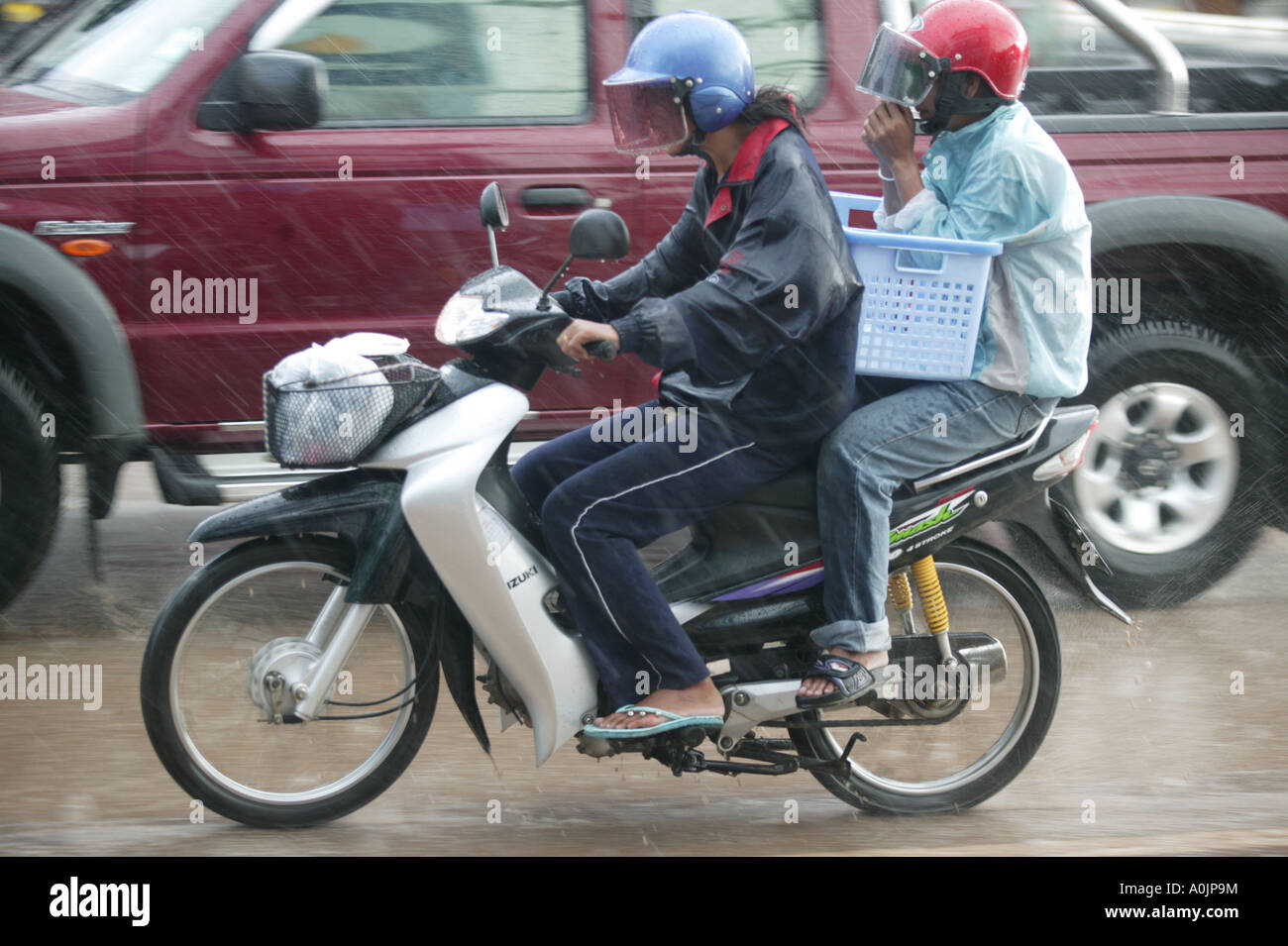 Two girls on a moped in the rain at Loei Stock Photo - Alamy