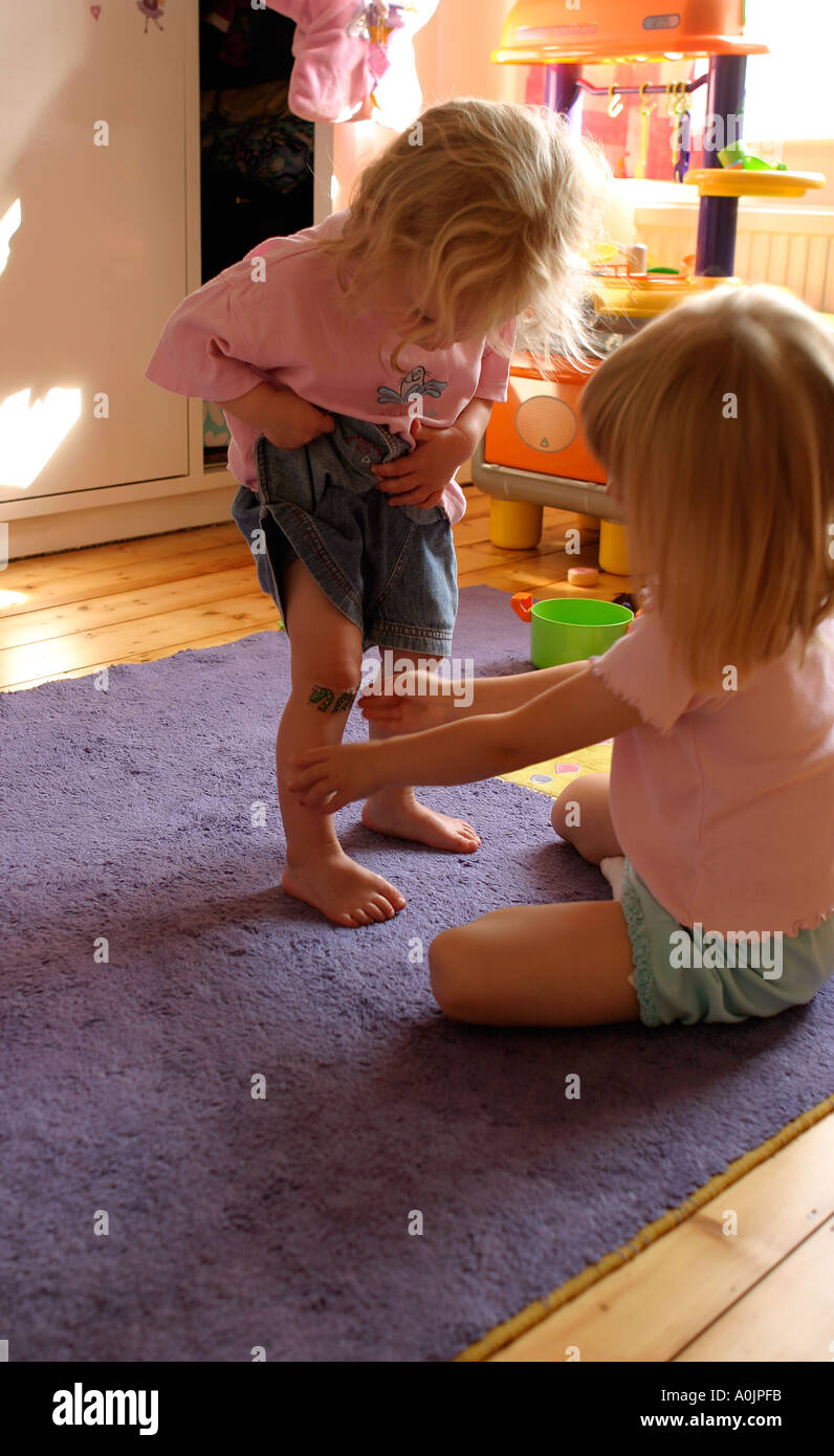 Girl putting a plaster on her sisters leg children playing at being ...
