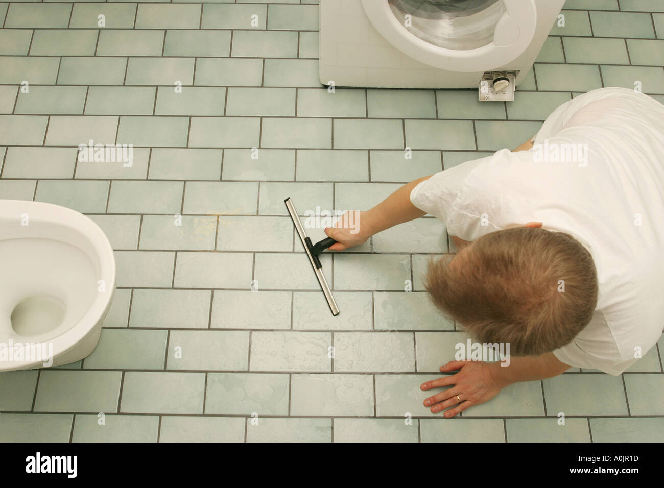 Man scraping the water off the bathroom floor Stock Photo - Alamy