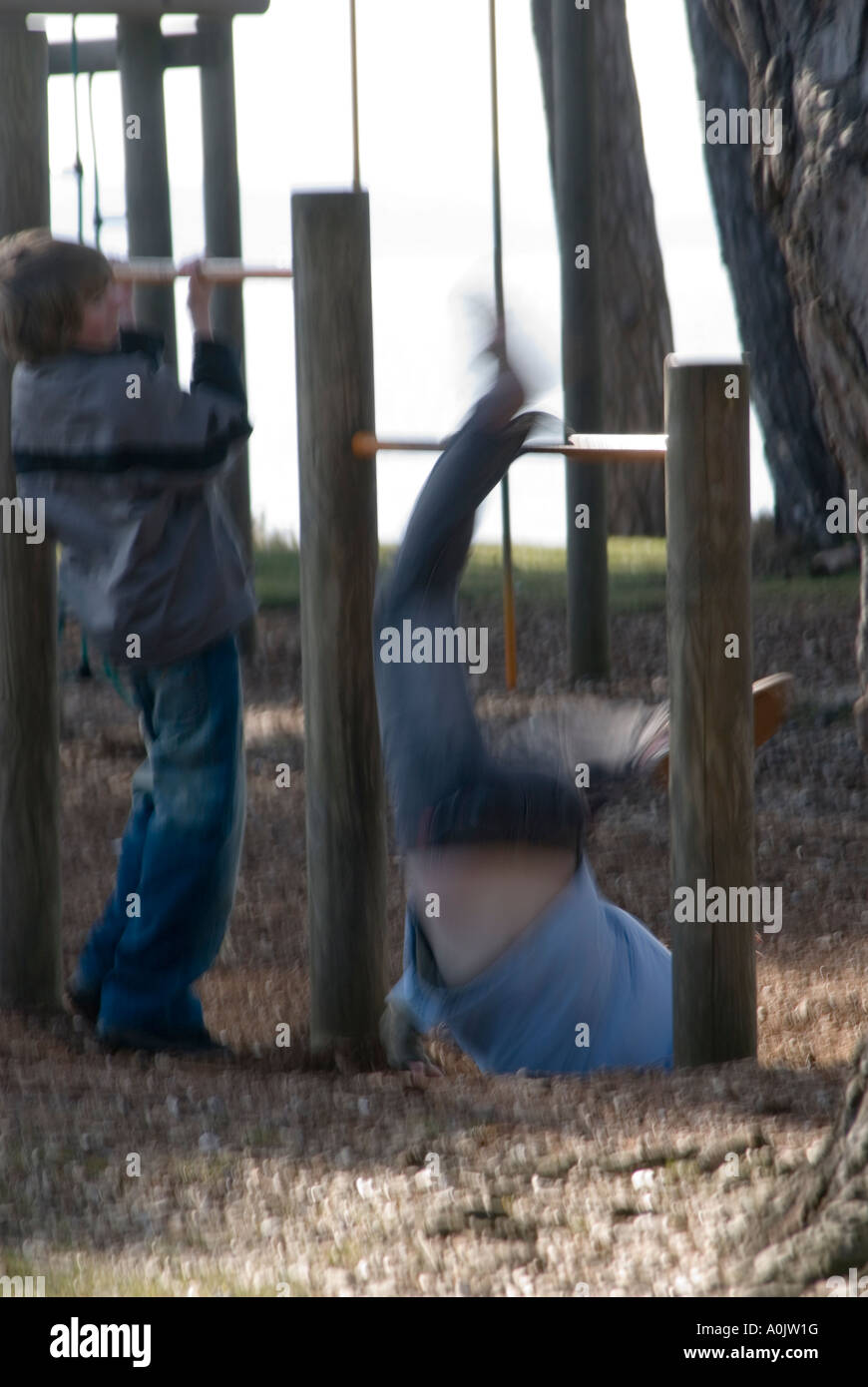 Two Teenagers in Playground with one falling off the equipment to the ...