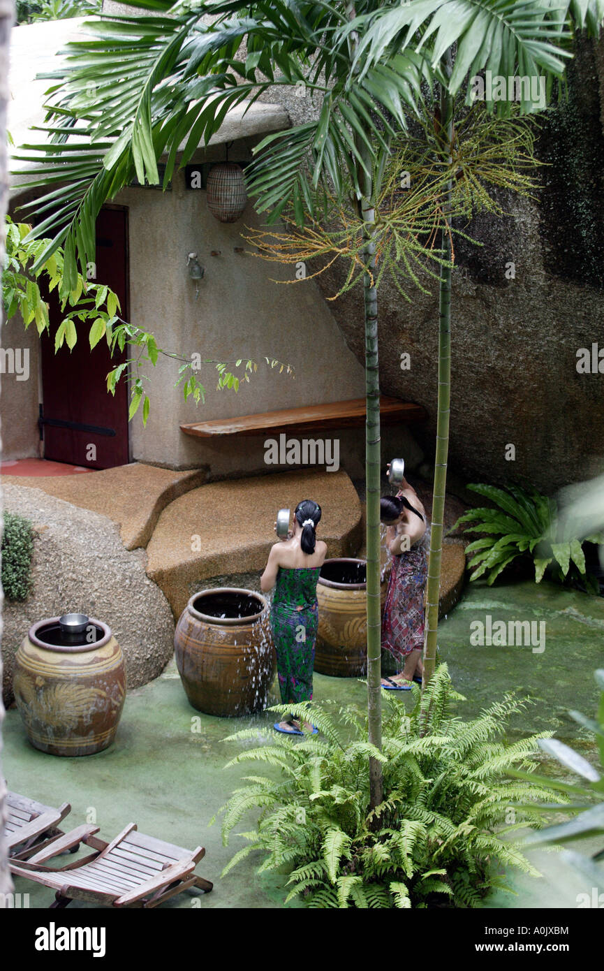 Two ladies in sarongs soak themselves using pots of water in the ...