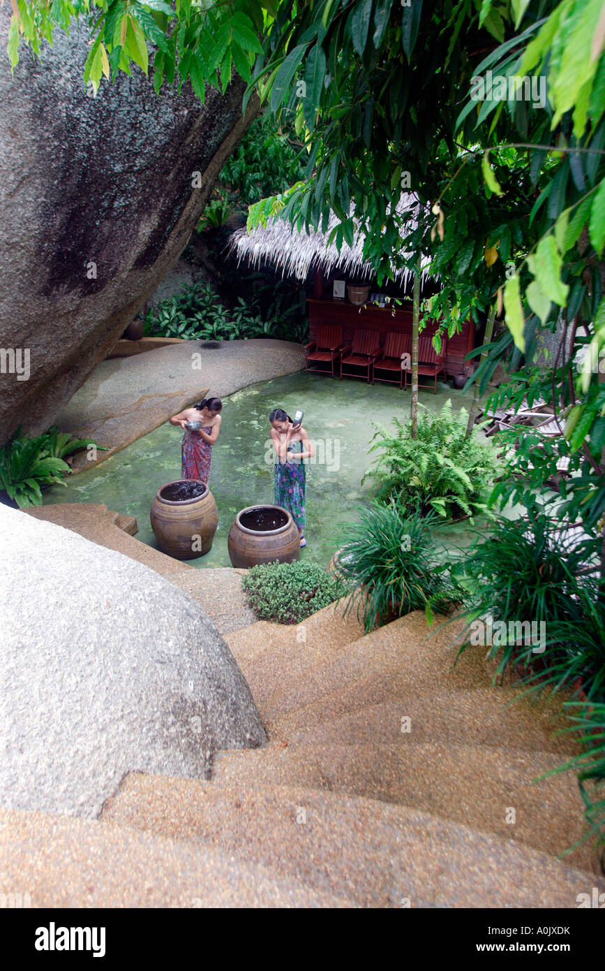 Two ladies in sarongs soak themselves using pots of water in the ...