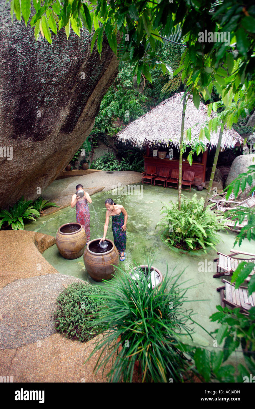 Two ladies in sarongs soak themselves using pots of water in the ...