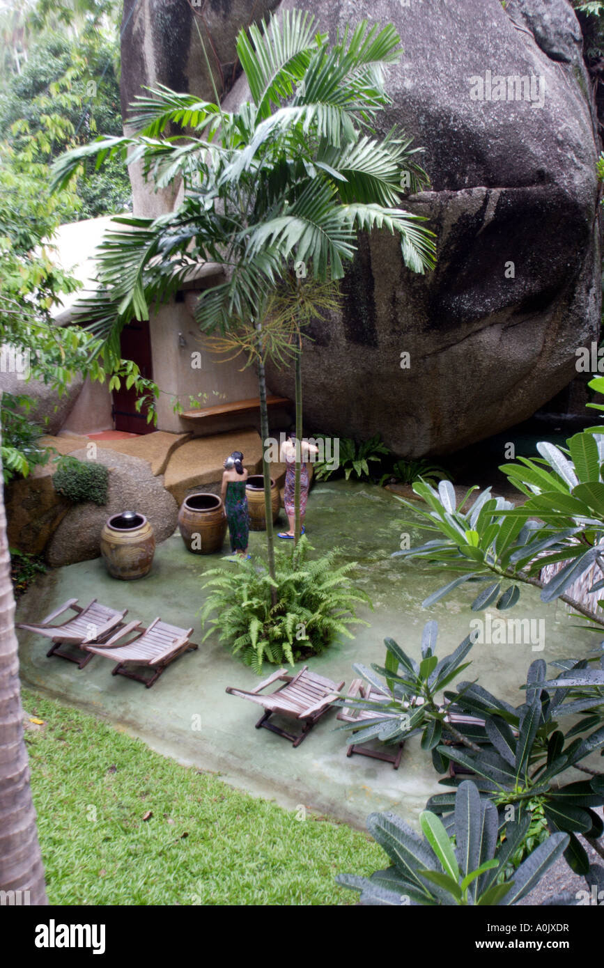 Two ladies in sarongs soak themselves using pots of water in the ...