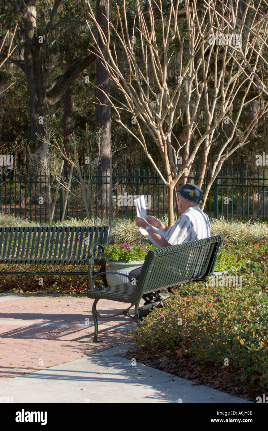 Elderly man reading newspaper on a bench in the park Stock Photo - Alamy