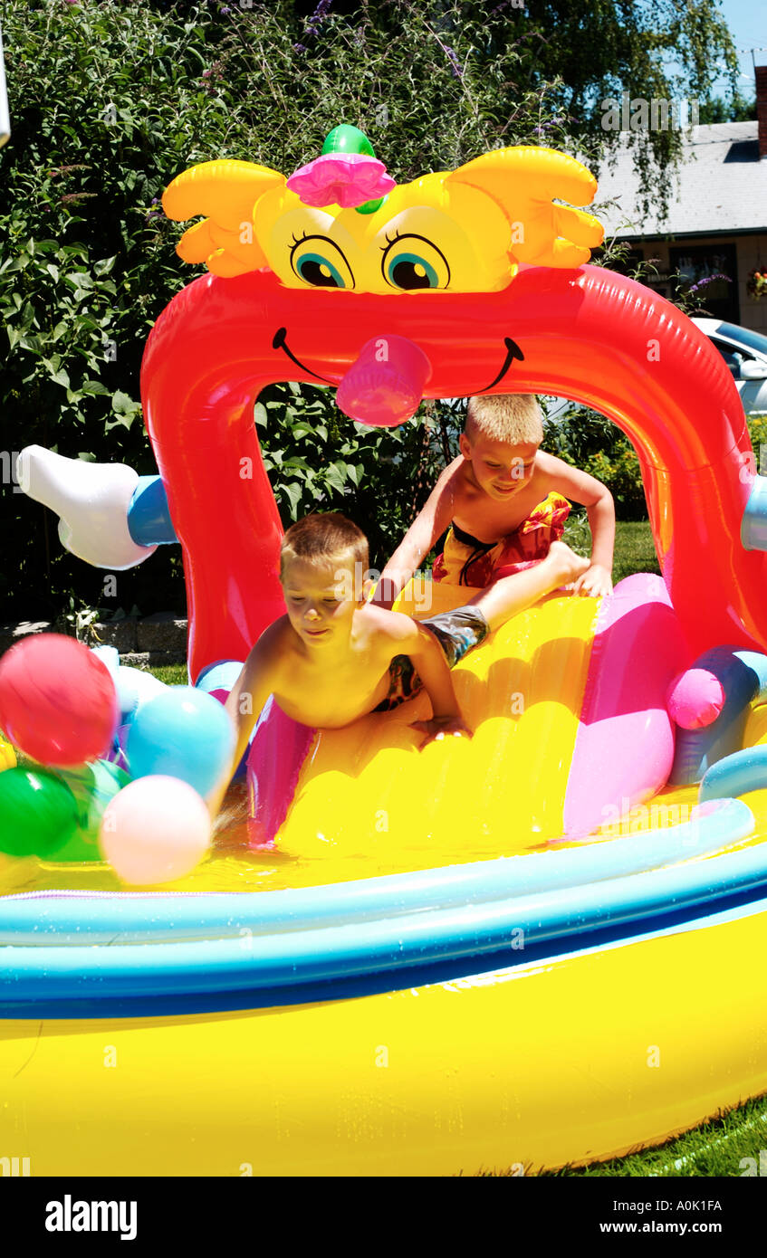 Two young boys sliding into inflatable pool Stock Photo - Alamy