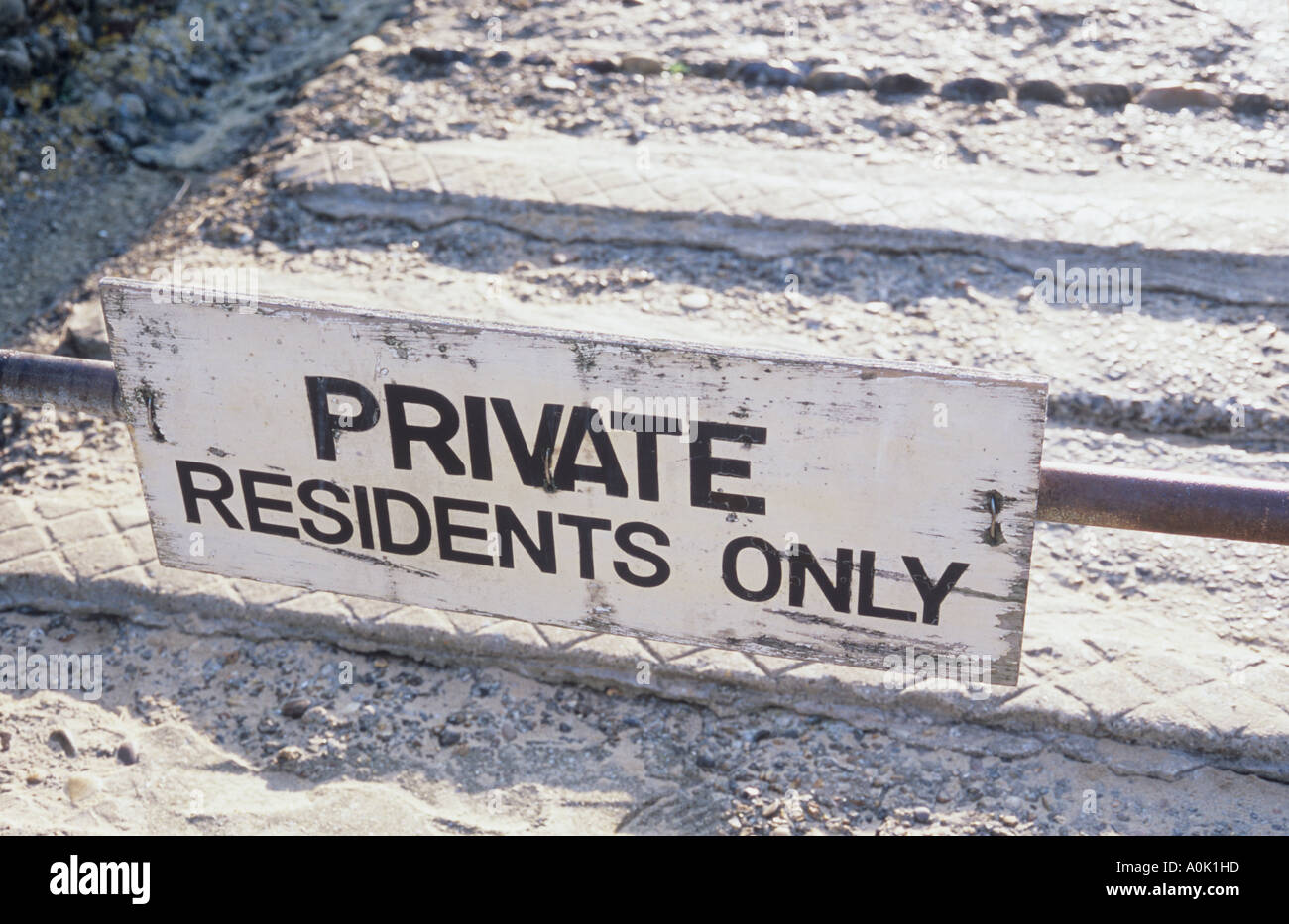 Weathered painted sign on a pole across cement concrete and flint steps ...