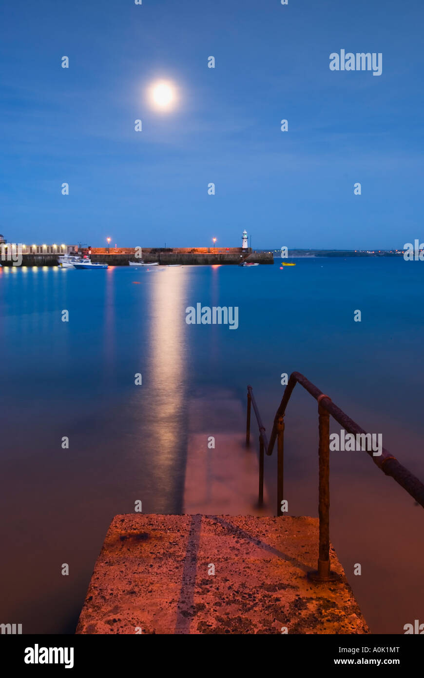St. Ives Harbour, Cornwall UK at night with the moon in the background ...