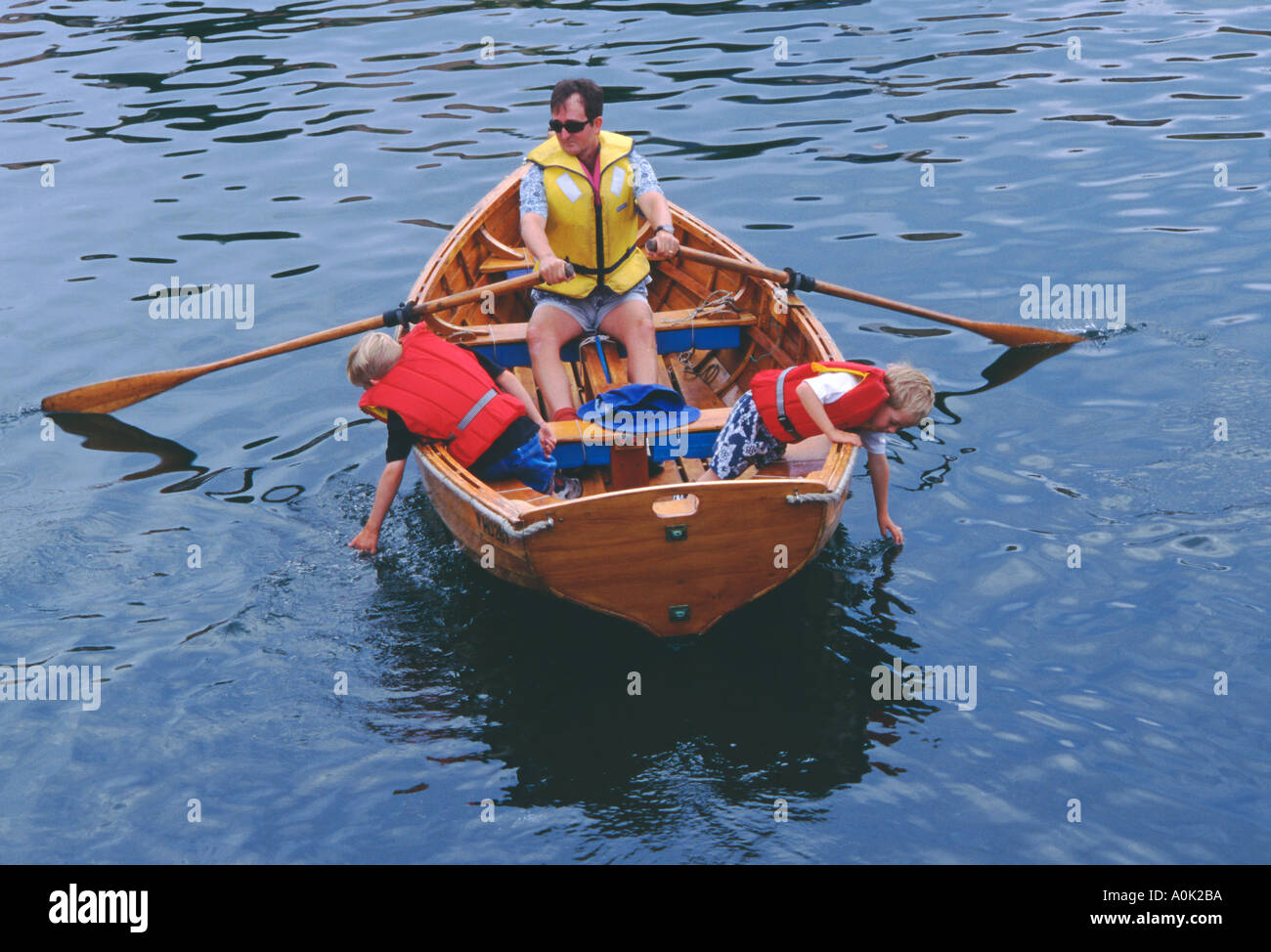 Man and two children rowing in traditional wooden dinghy Stock Photo ...