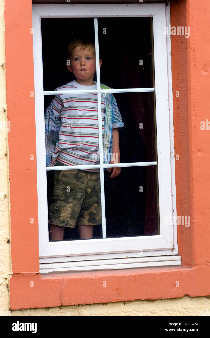A young boy looks out through the window of a house Stock Photo - Alamy