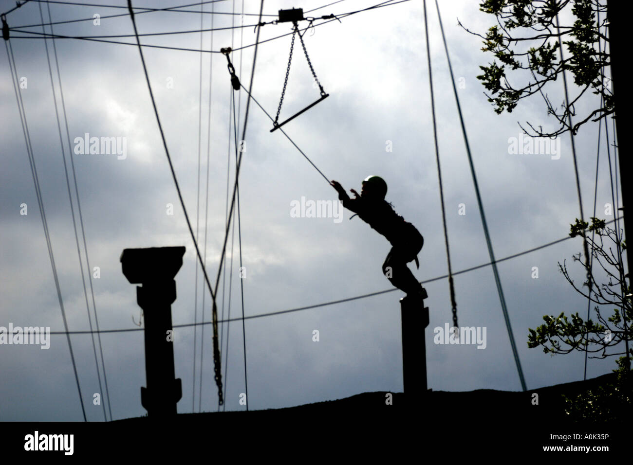 A person prepares to leap for a bar on a high ropes course Stock Photo ...
