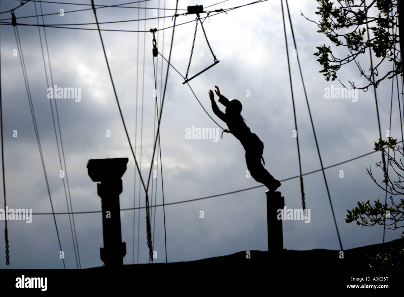 A person jumps for a bar on a high ropes course Stock Photo - Alamy