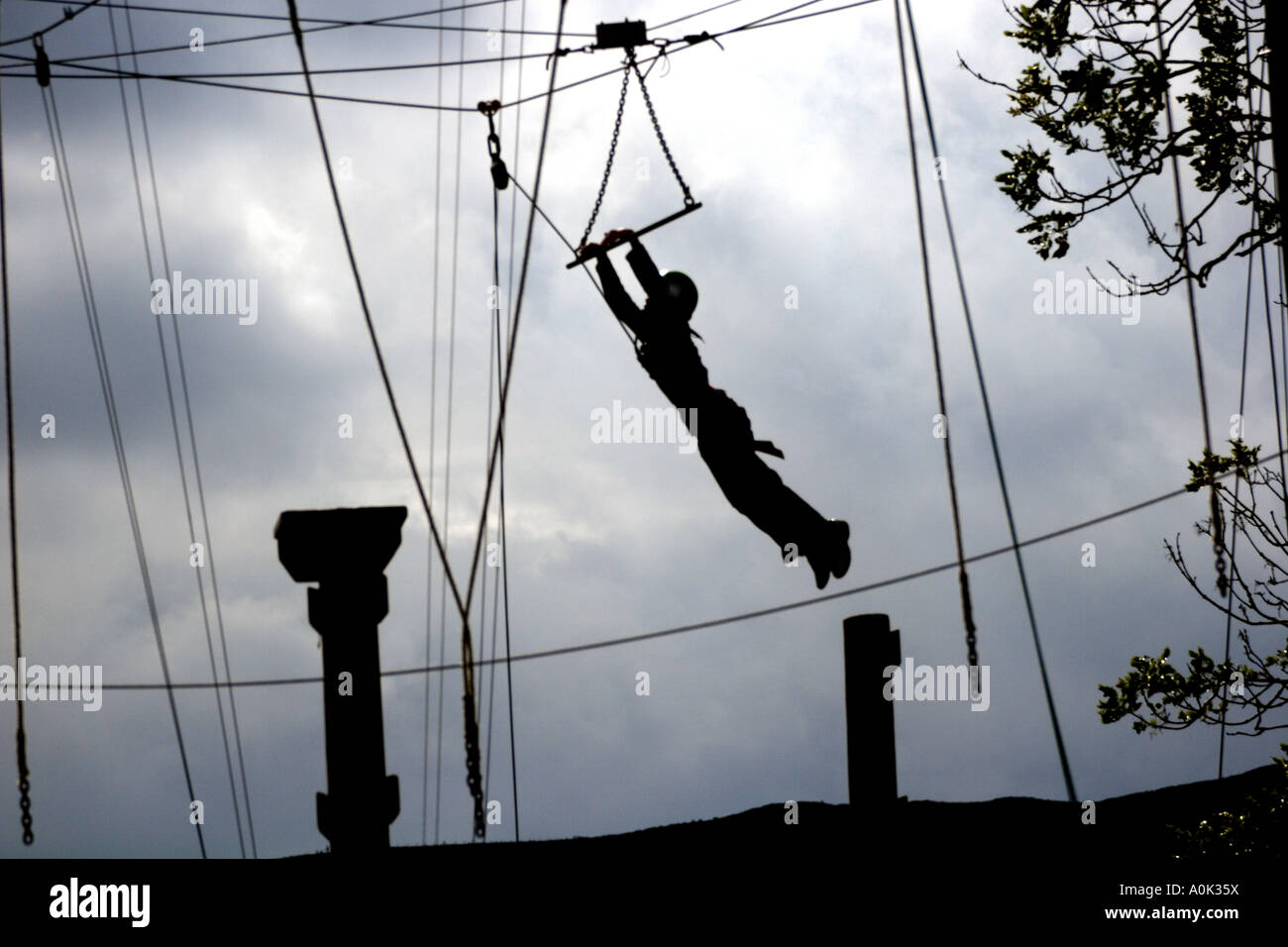 A person jumps for a bar on a high ropes course Stock Photo - Alamy