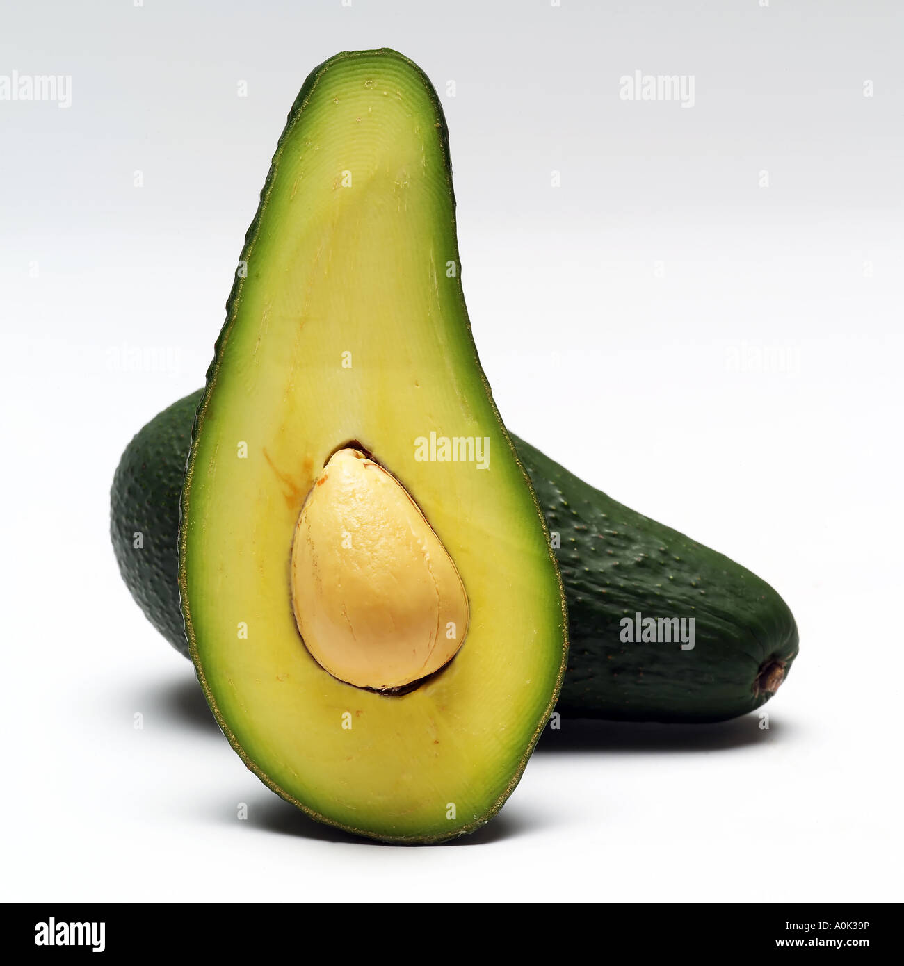 Halved avocado with stone and a whole avocado Stock Photo - Alamy