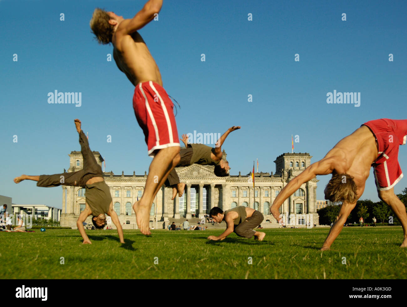 Stunt men practising a sport flip on the green in front of the German ...