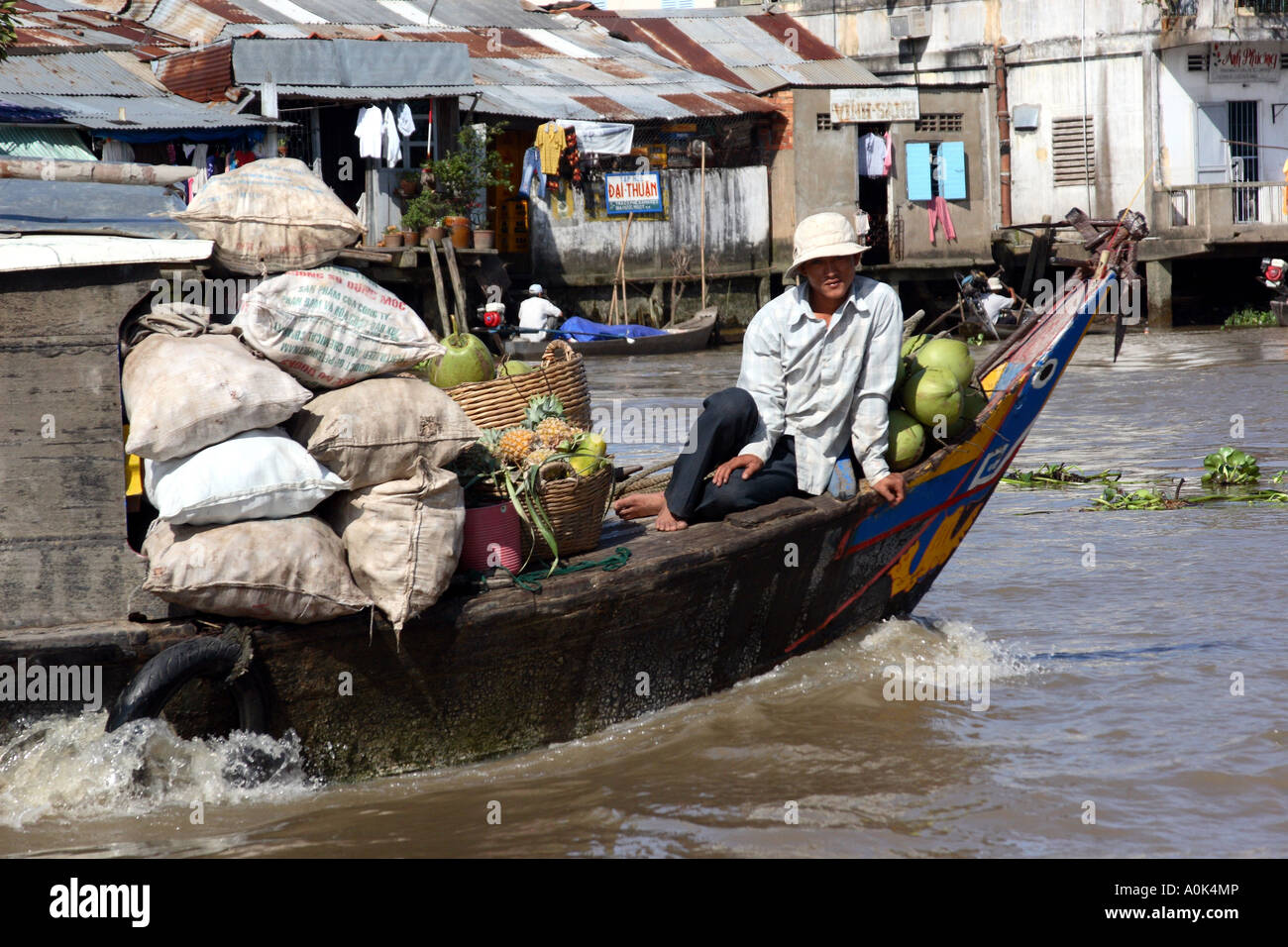 A boat loaded with rice and vegetables sailing along a river in the ...