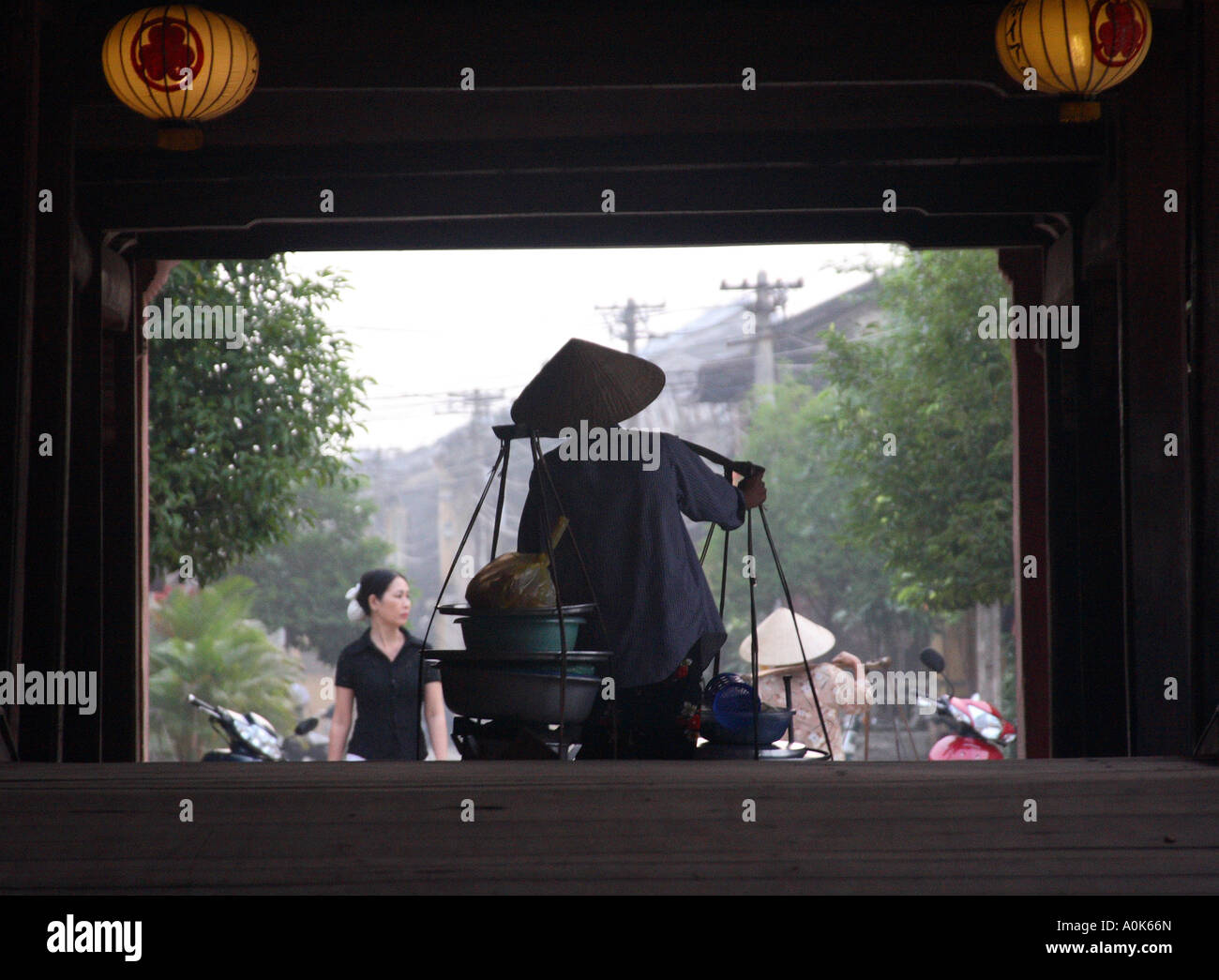 A food seller crossing the Japanese Covered Bridge in historic Hoi An ...