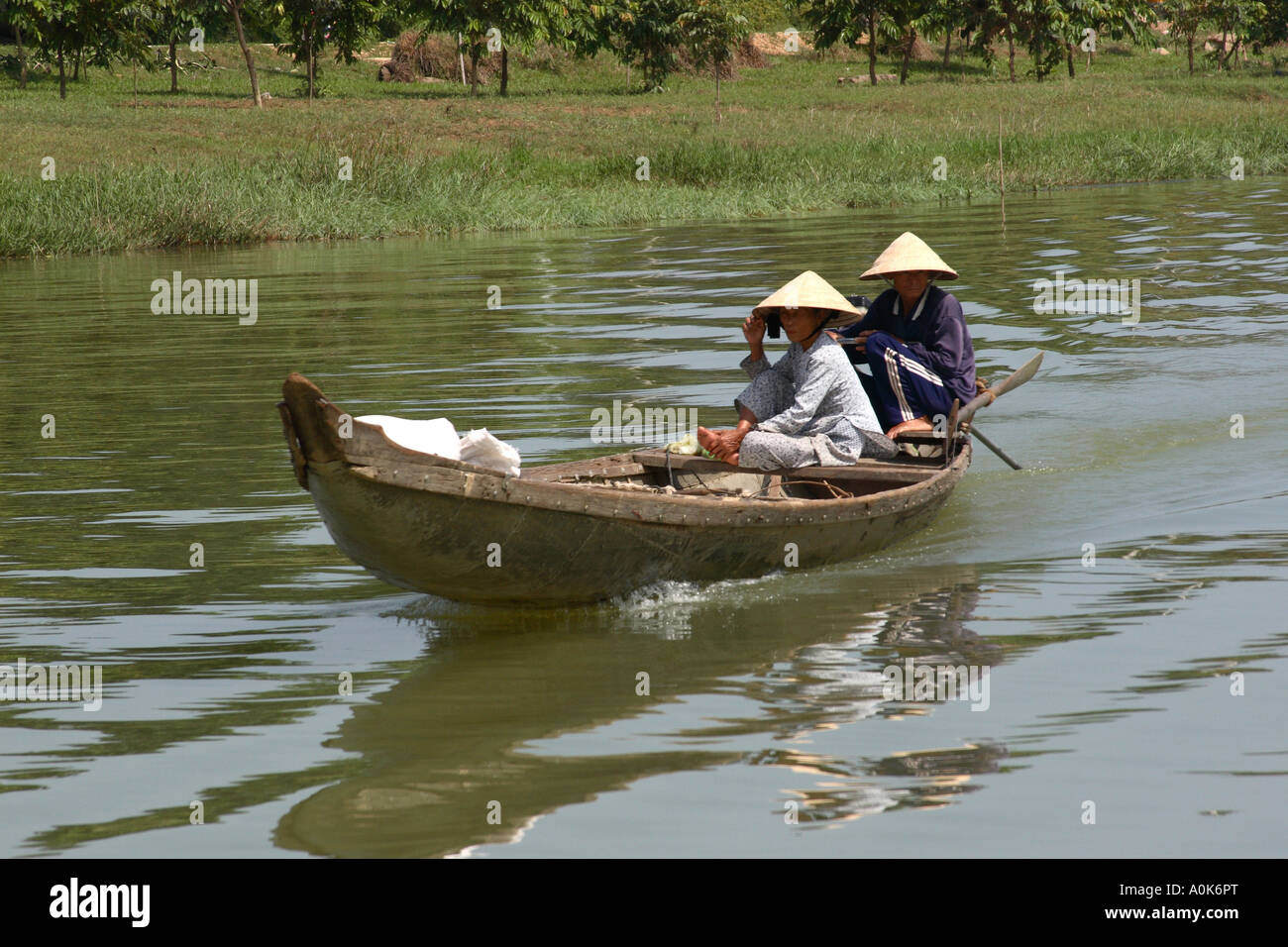 Two women steering a sampan along the Perfume River in the city of Hue ...