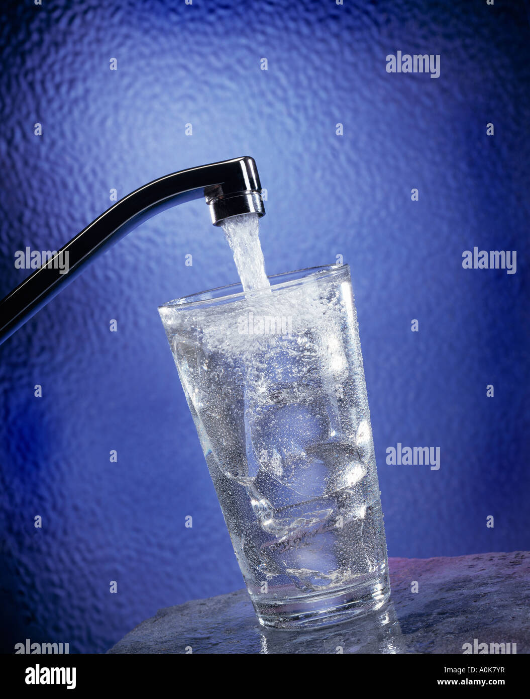 Water pouring from faucet with blue background Stock Photo - Alamy