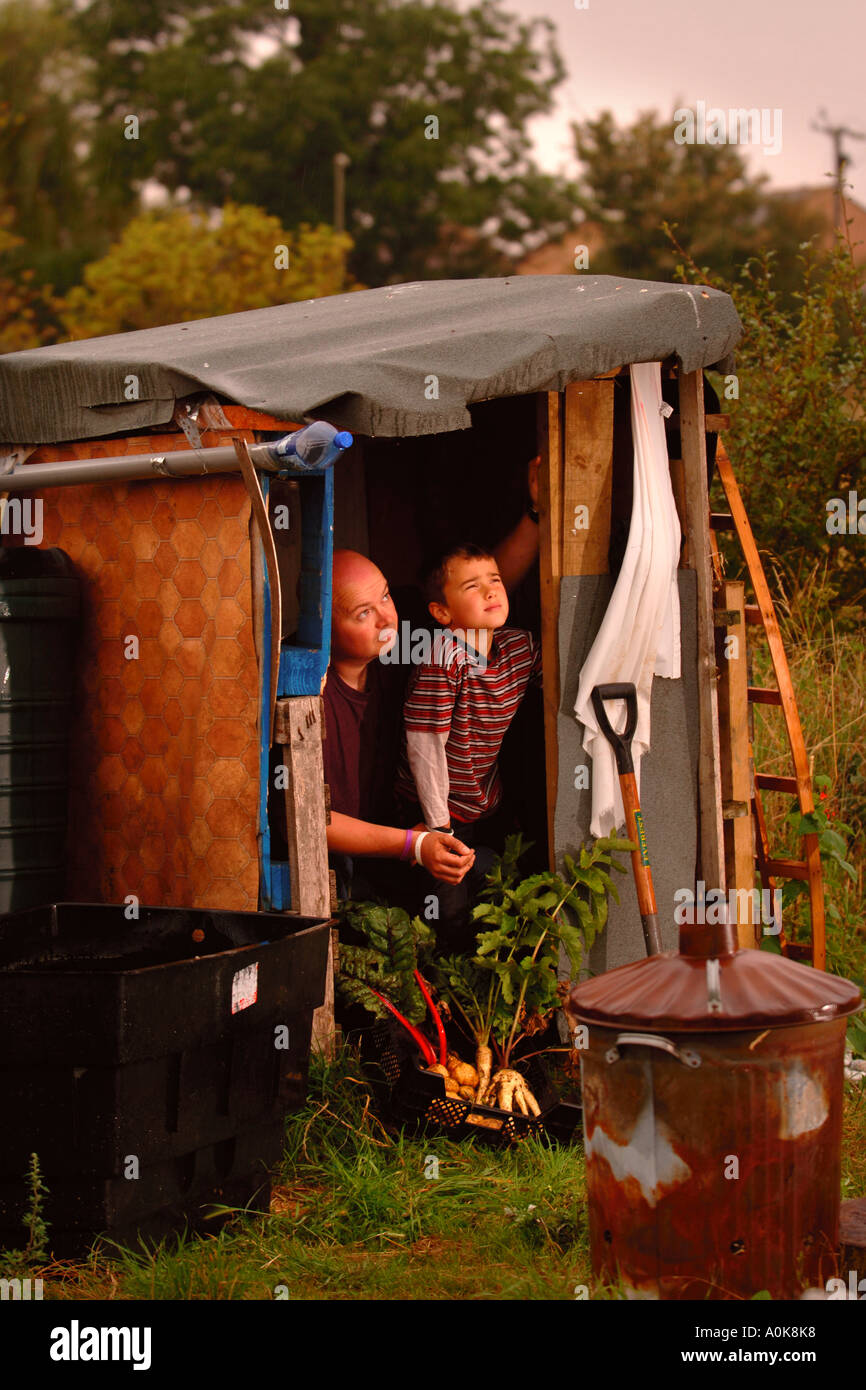 A FATHER AND SON TAKE SHELTER FROM THE RAIN IN A MAKESHIFT SHED ON AN ...