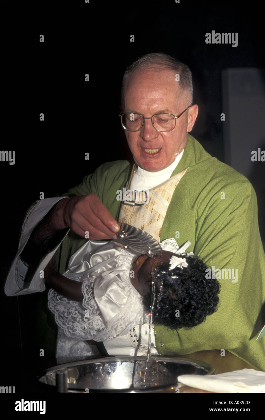 A white Catholic priest baptising a black child in South London Stock ...