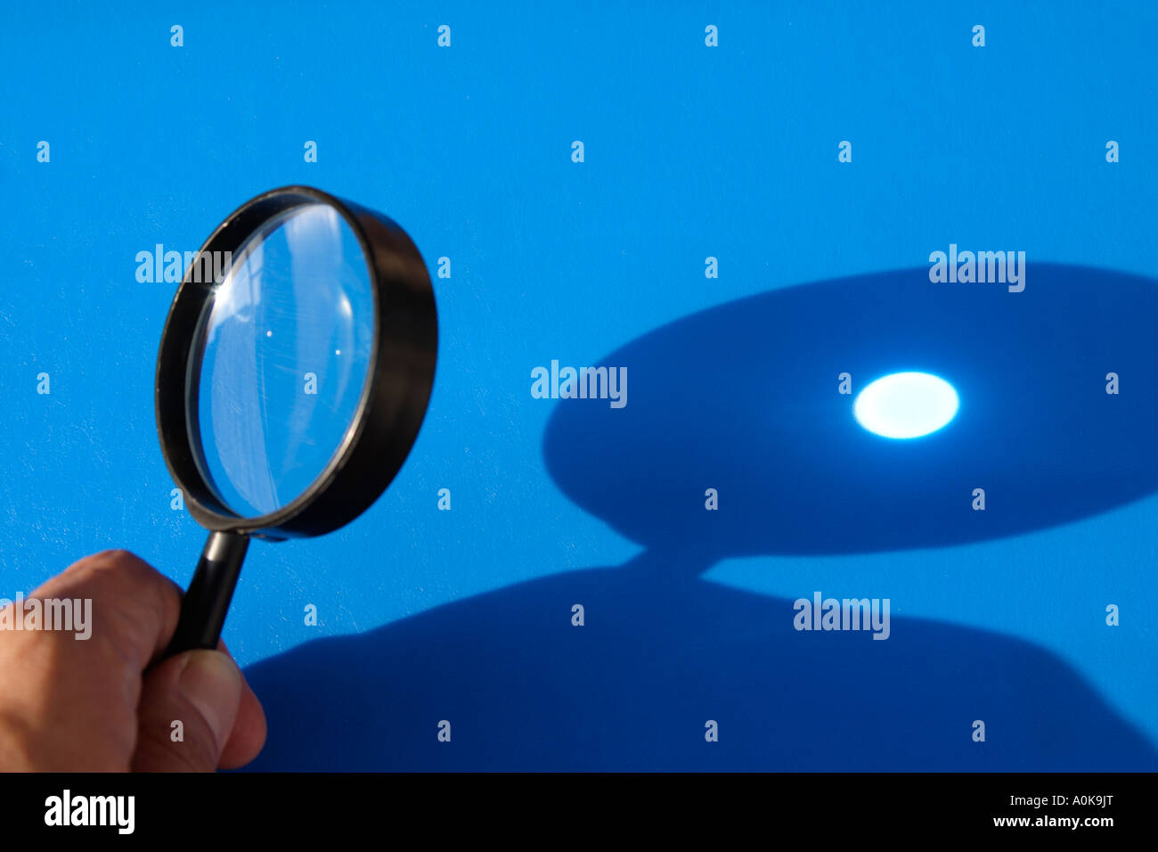 spot of light from sun focused by magnifying glass on blue surface ...