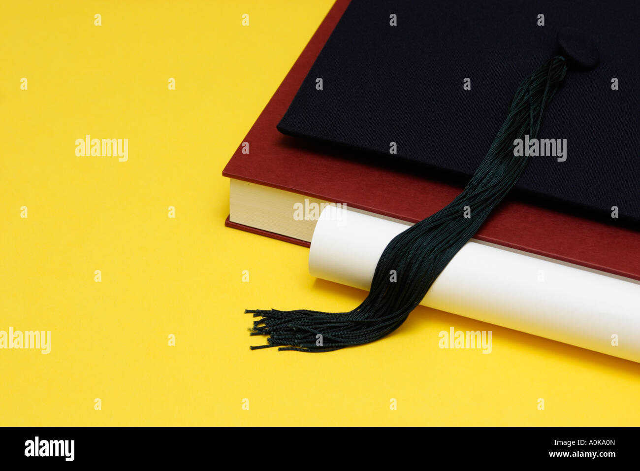 graduation cap on top of a thick book and scroll of paper Stock Photo ...