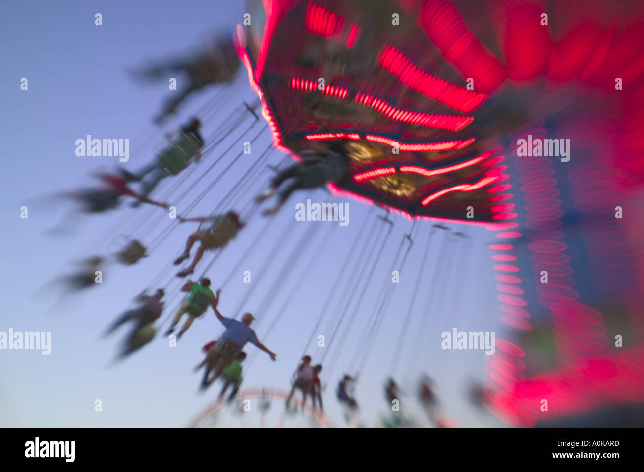 Swing ride lit up in evening on the midway and two people reaching for ...