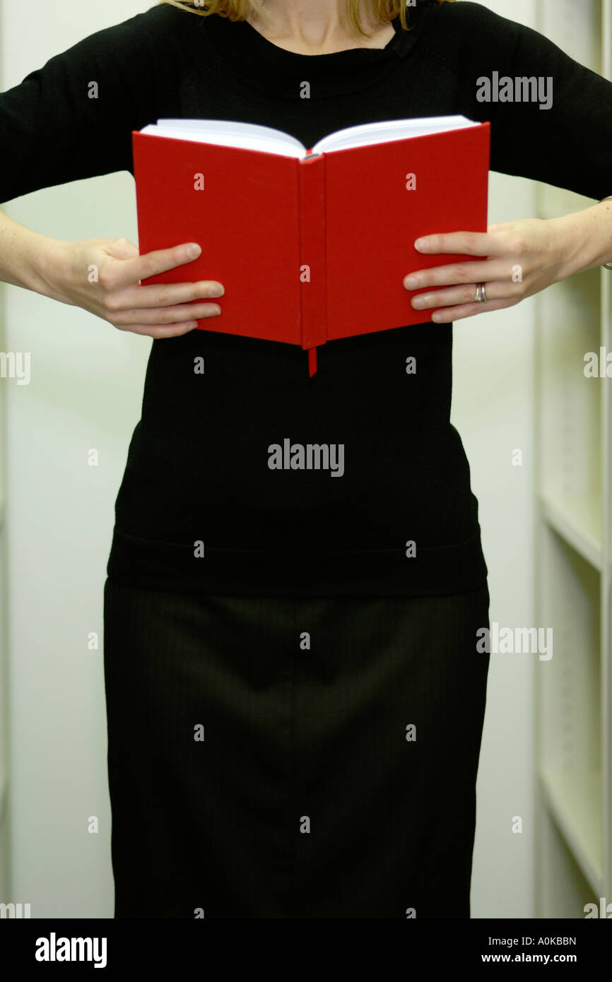 woman standing between shelves reading book Stock Photo - Alamy