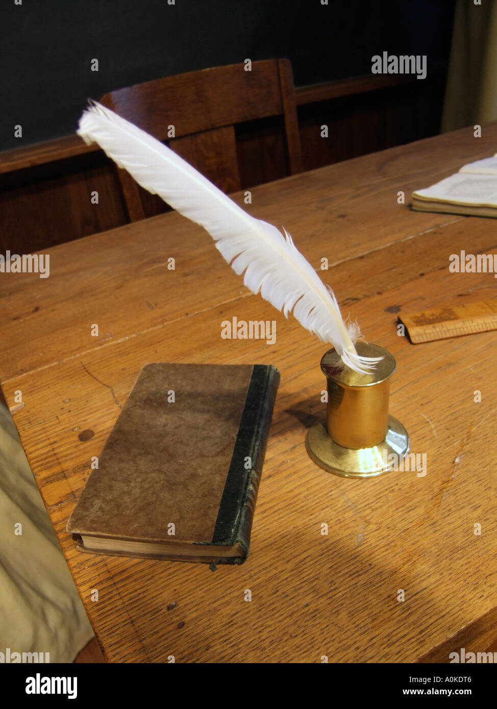 Historic feather pen and ink well on a desk along side of a book Stock ...