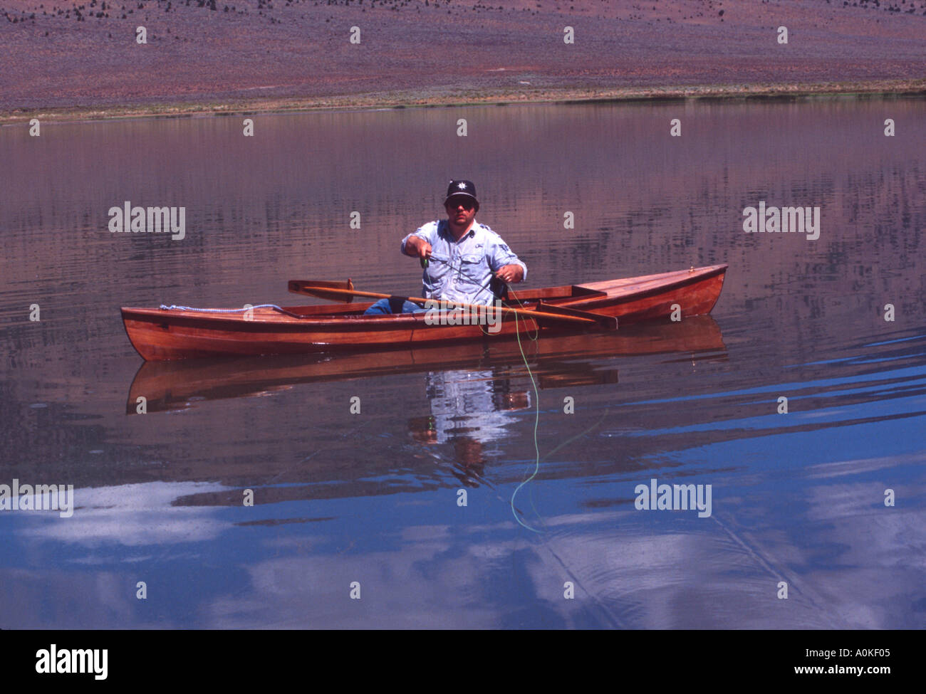man casting fly from decked wooden double paddle canoe Mann Lake ...