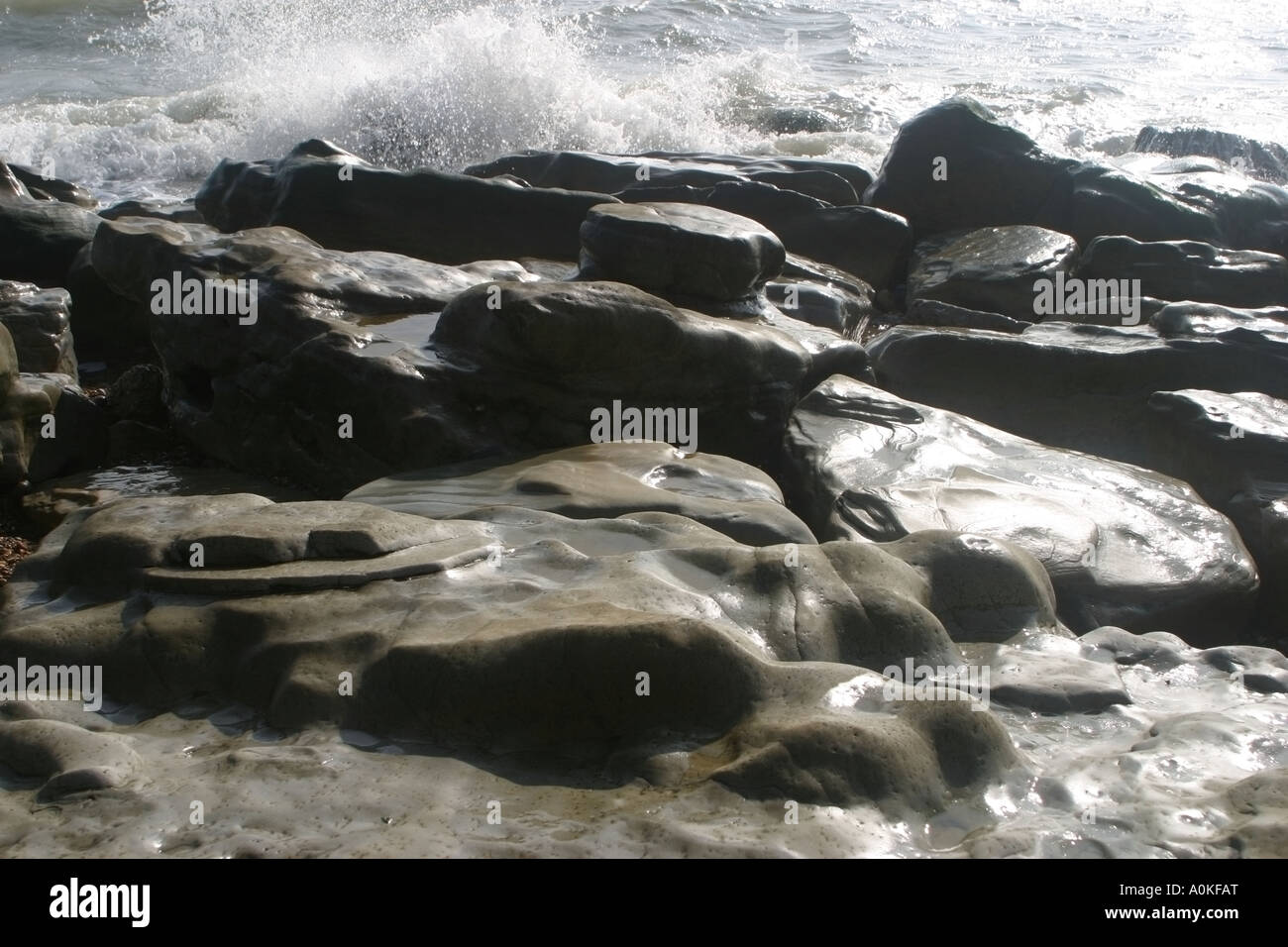 The sea hitting smooth rocks on beach Stock Photo - Alamy