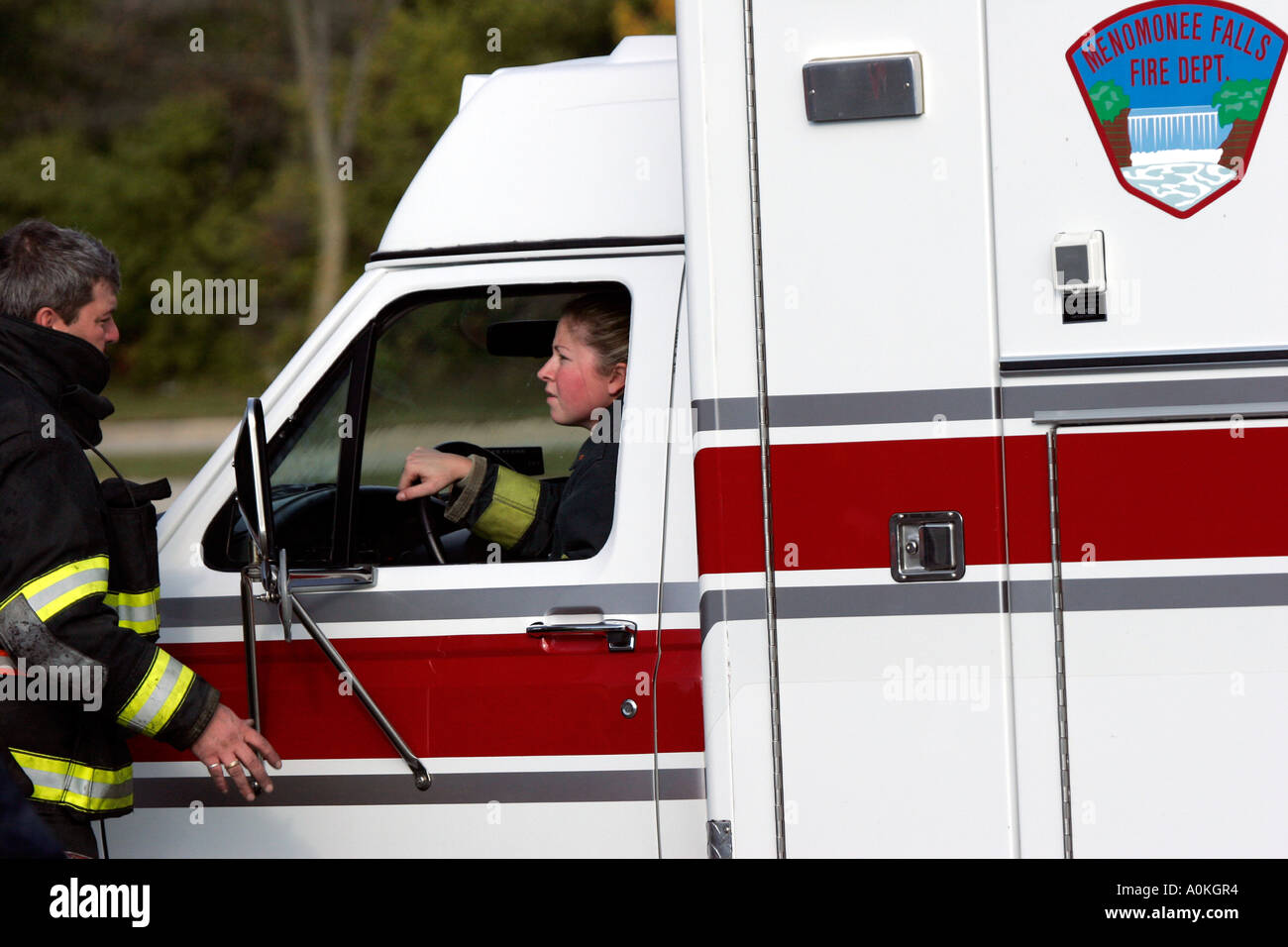 A women EMT driver in an ambulance is talking to a fire fighter on ...