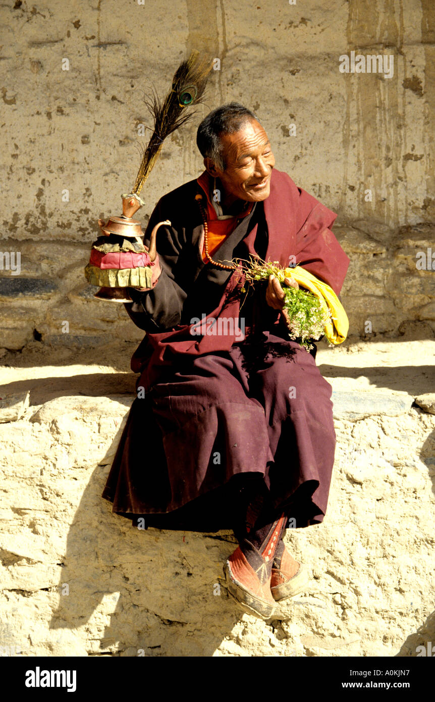 Smiling monk with ceremonial teapot and peacock feather in western ...