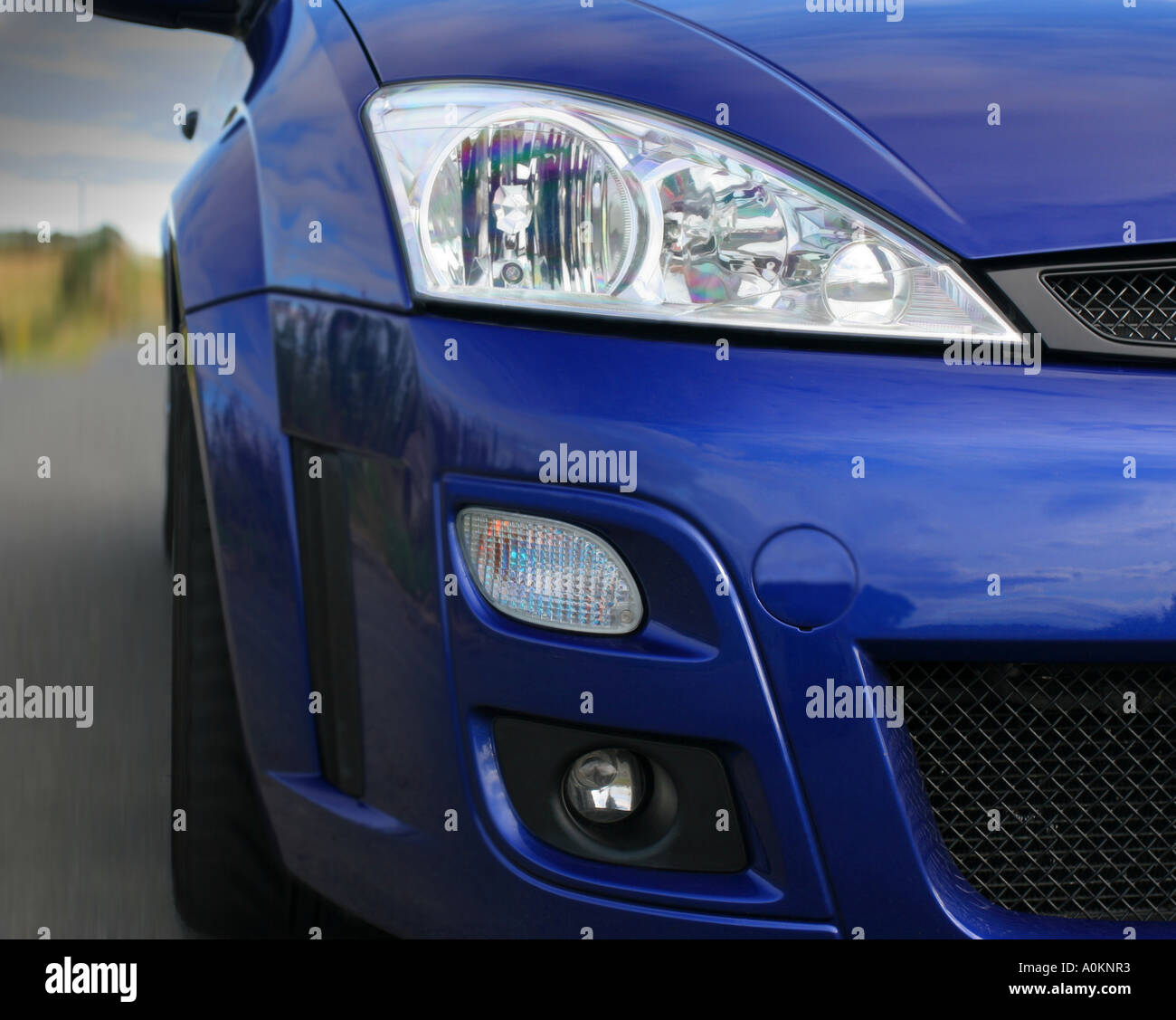 A full frame image of the front of a deep blue sports car moving on a ...