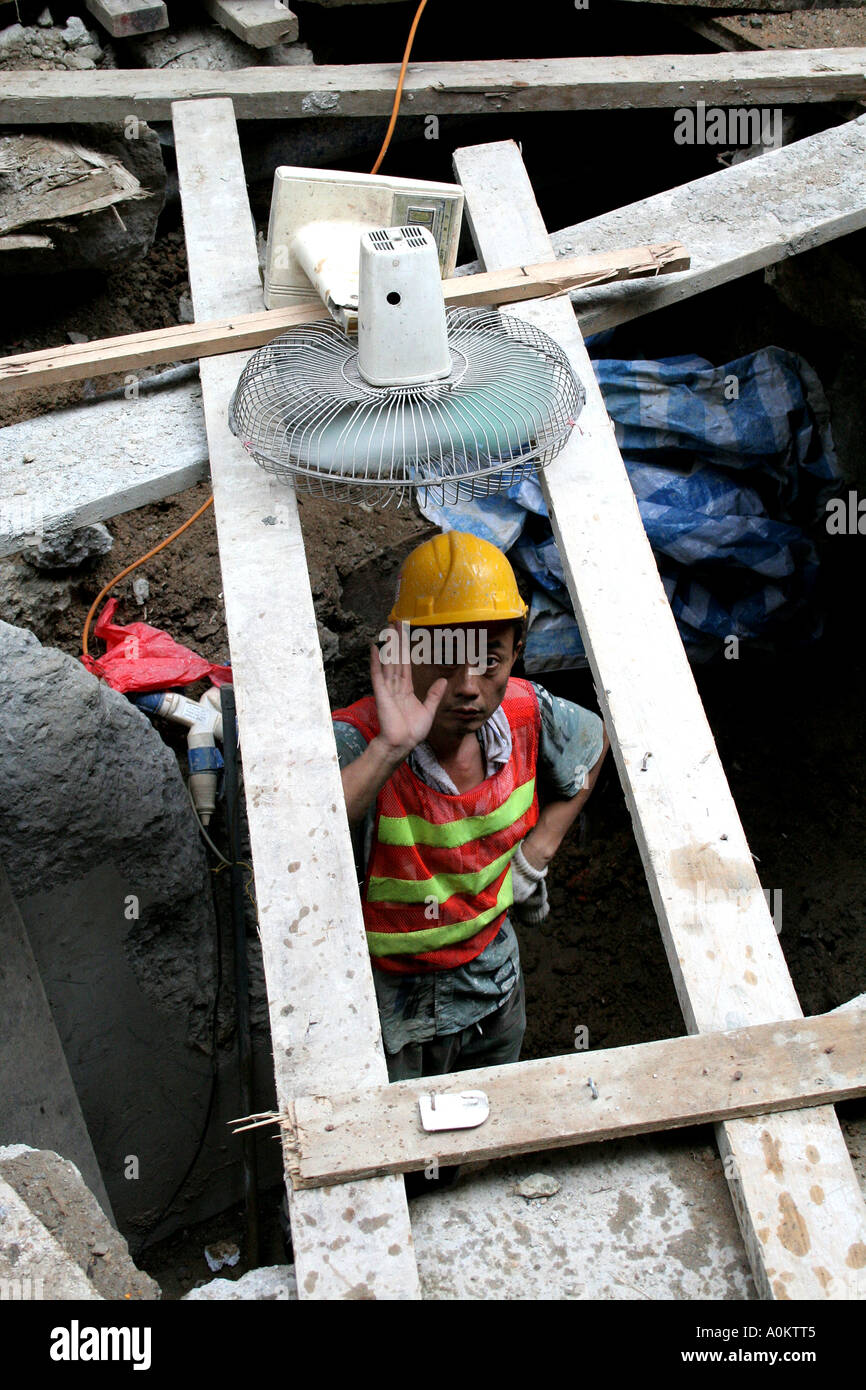 Construction worker waves from where he works below the ground in ...