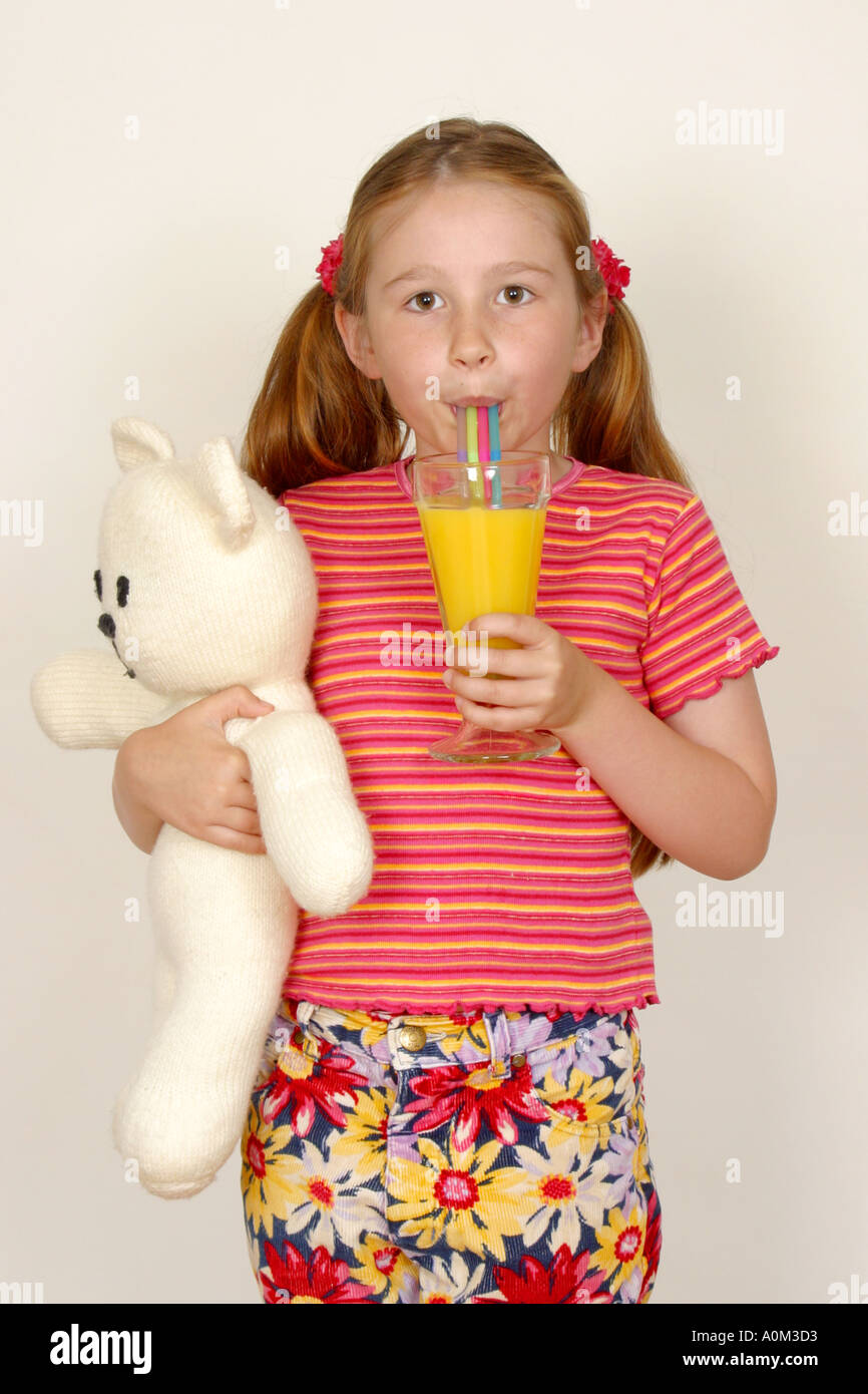 Girl holding teddy drinking orange juice with straw Stock Photo - Alamy