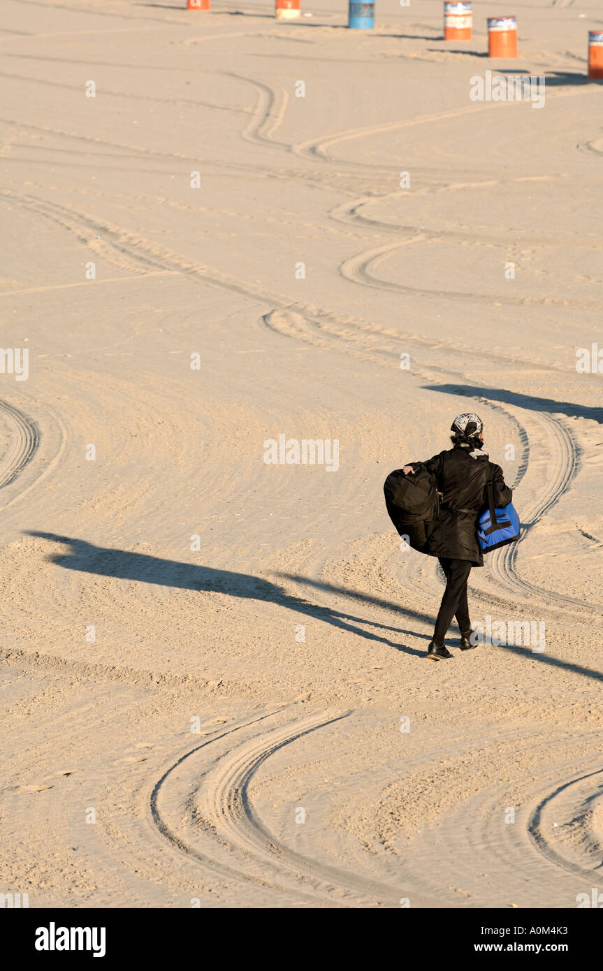 Homeless woman carrying all her belongings in bags walking along the ...