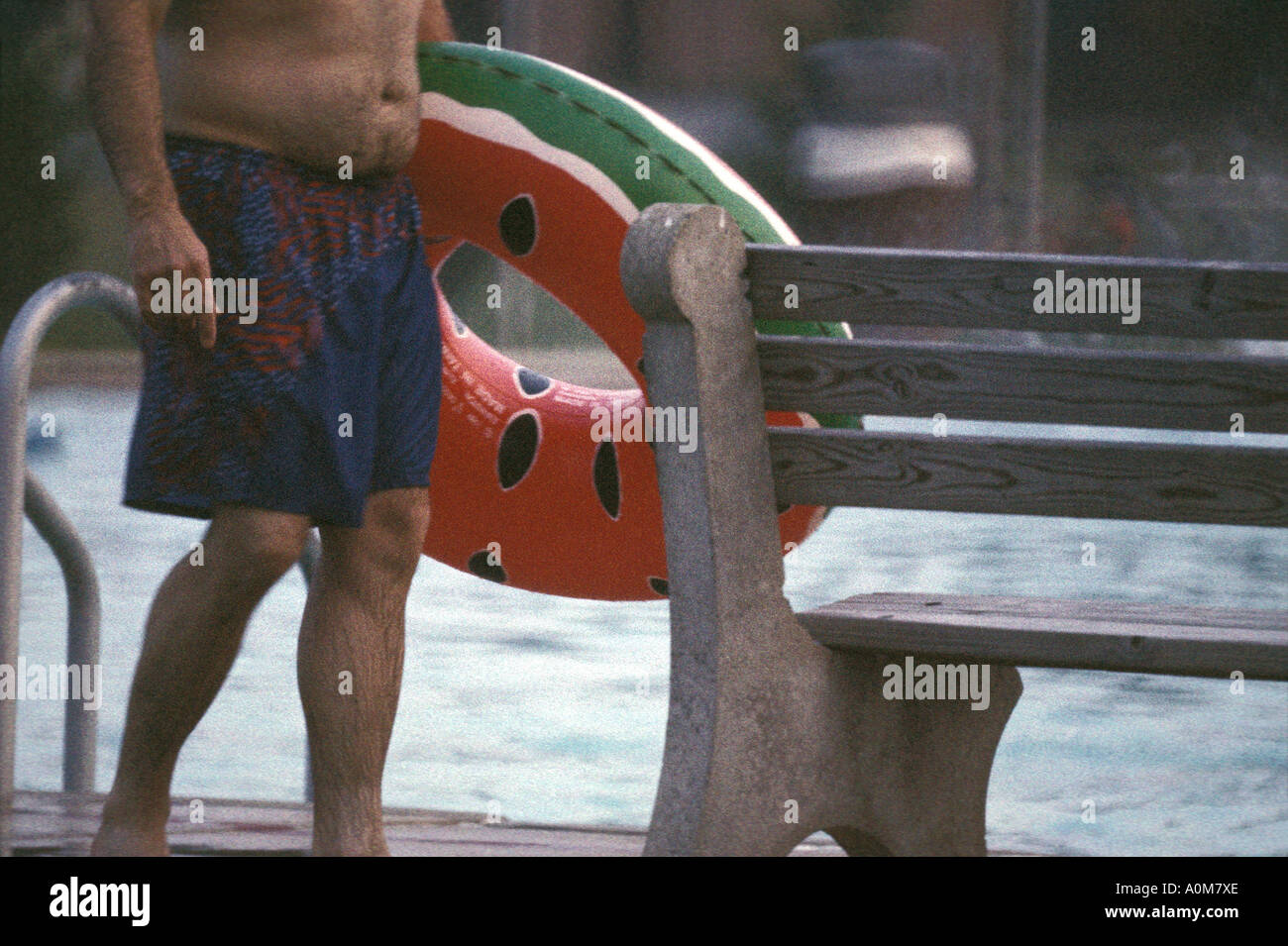 young boy large tube ring public swimming pool bench swim suit teen ...