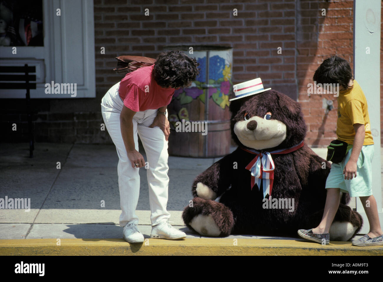 mother daughter inspect gigantic teddy bear along street small town ...